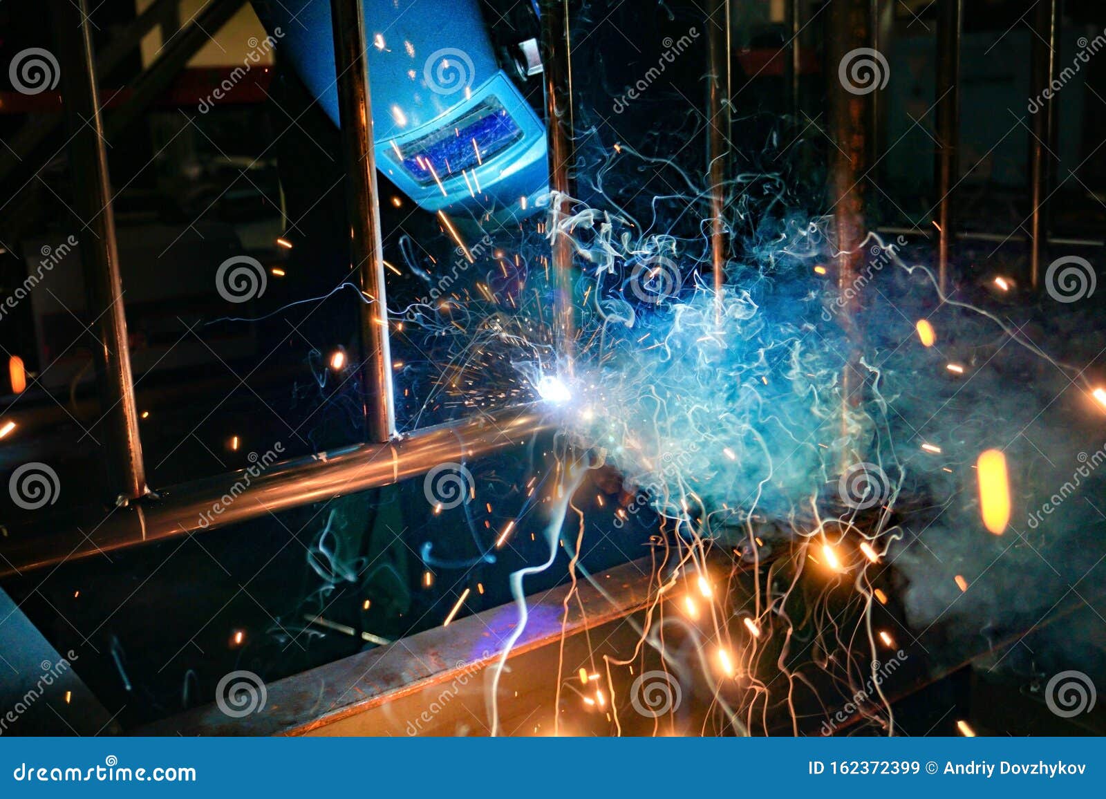 A Welder at Work in a Workshop Produces Metal Structures. Sparks from ...