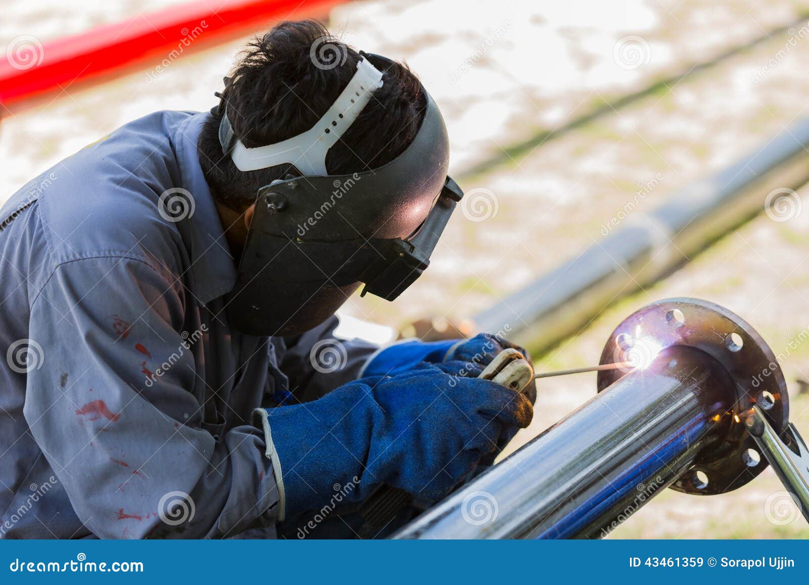 Welding Work. A Worker In Overalls And A Protective Mask Welds The ...