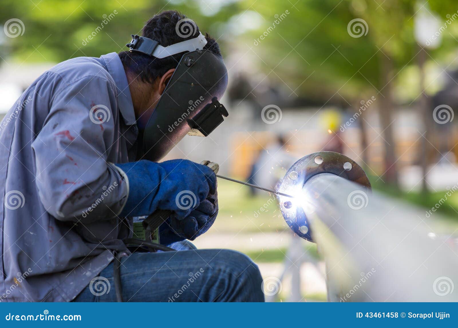Welding Work. A Worker In Overalls And A Protective Mask Welds The ...