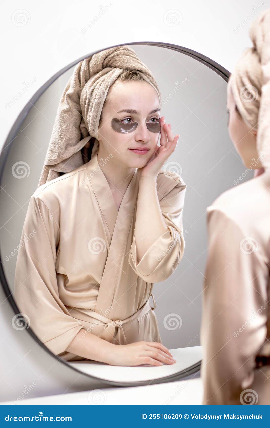 A Well Groomed Woman At Home In A Bathrobe And Towel Applies Patches