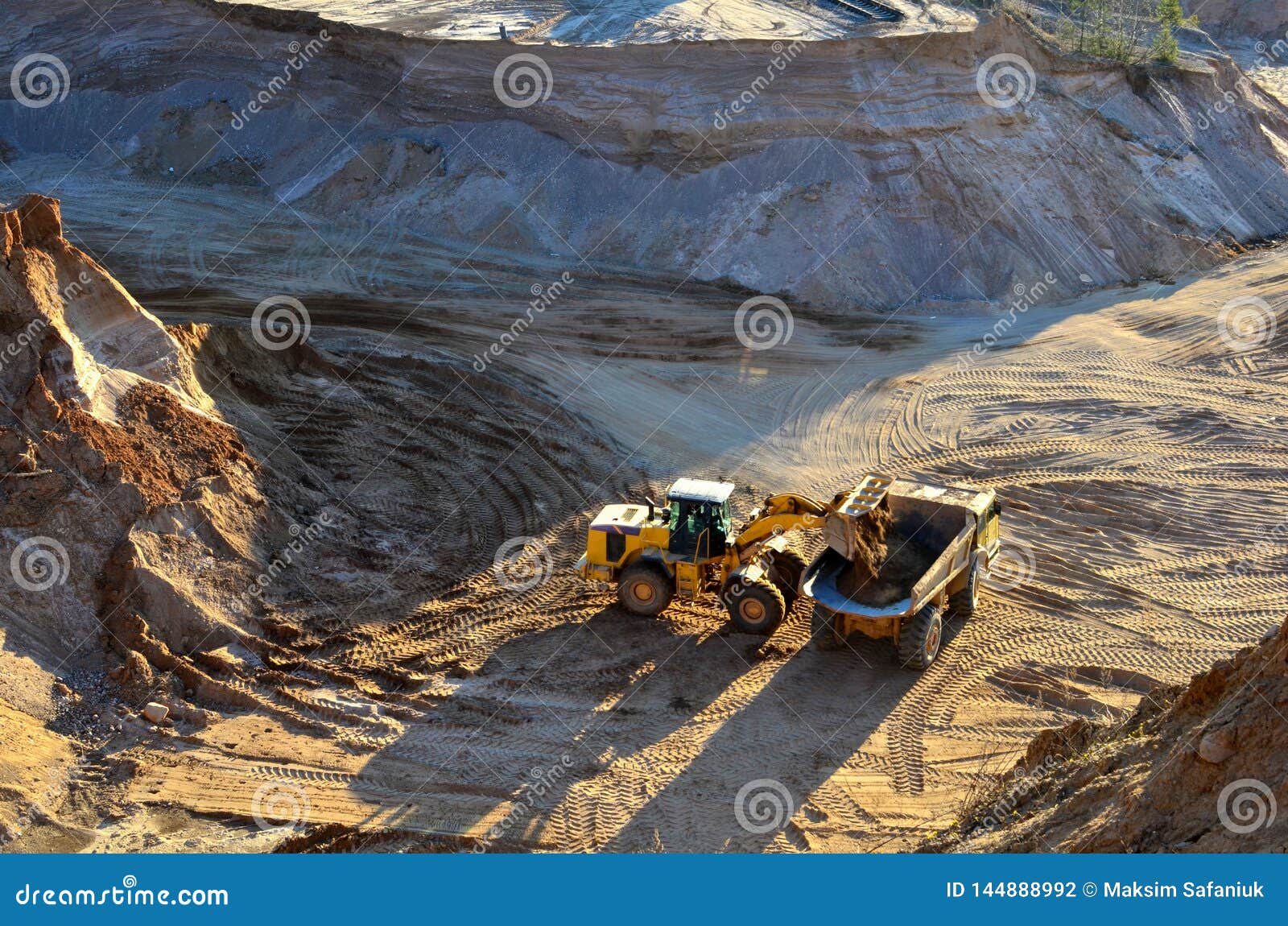 Wheel Front-end Loader Unloading Sand into Heavy Dump Truck at the ...
