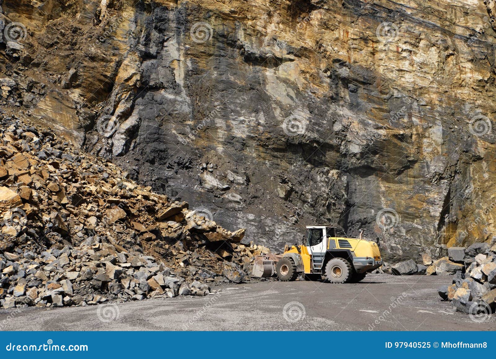 A Wheel Loader Machine Working on a Large Heap of Stones in Front of a ...