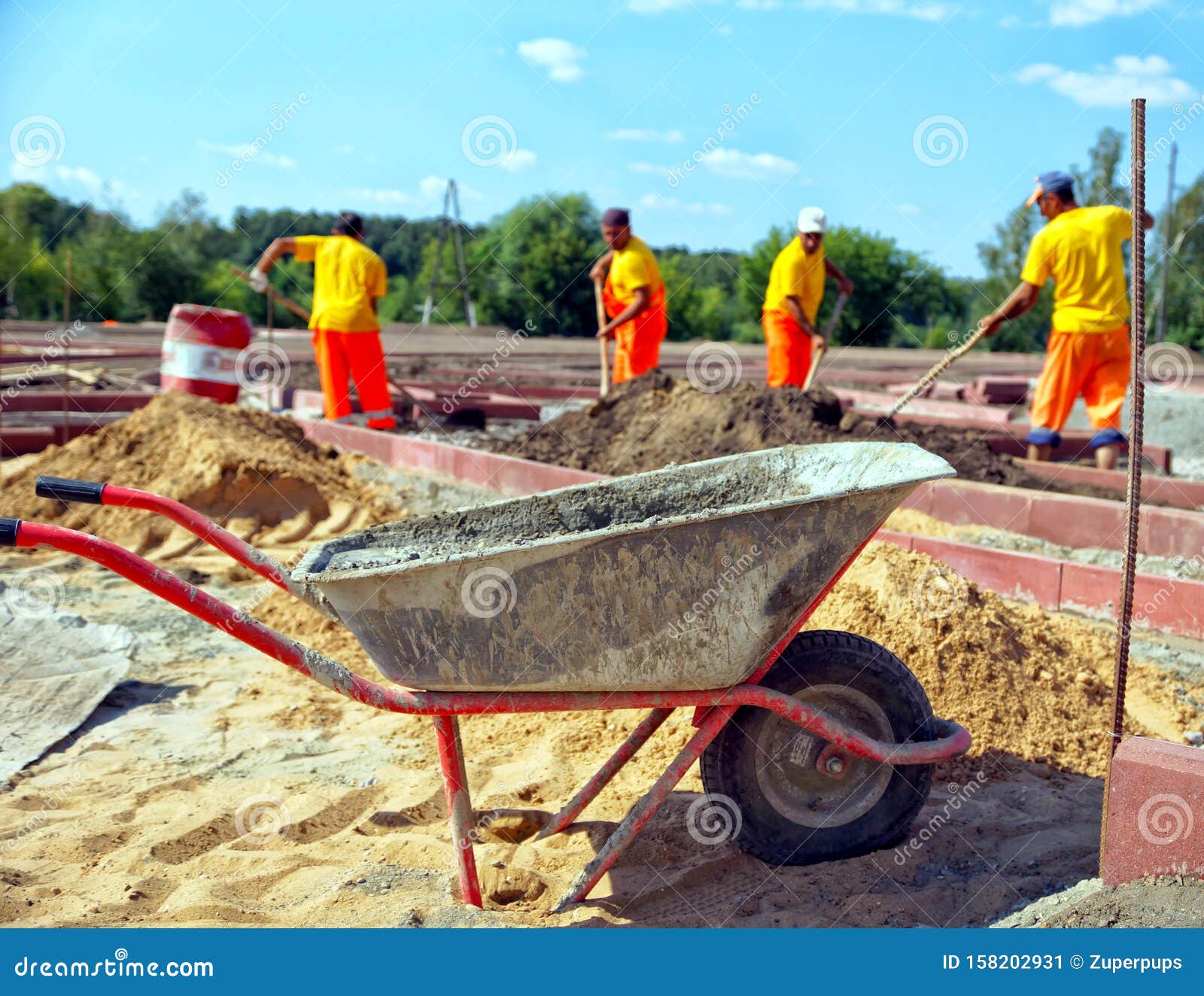 Wheelbarrow with Concrete on a Construction Site, Workers in Uniform ...