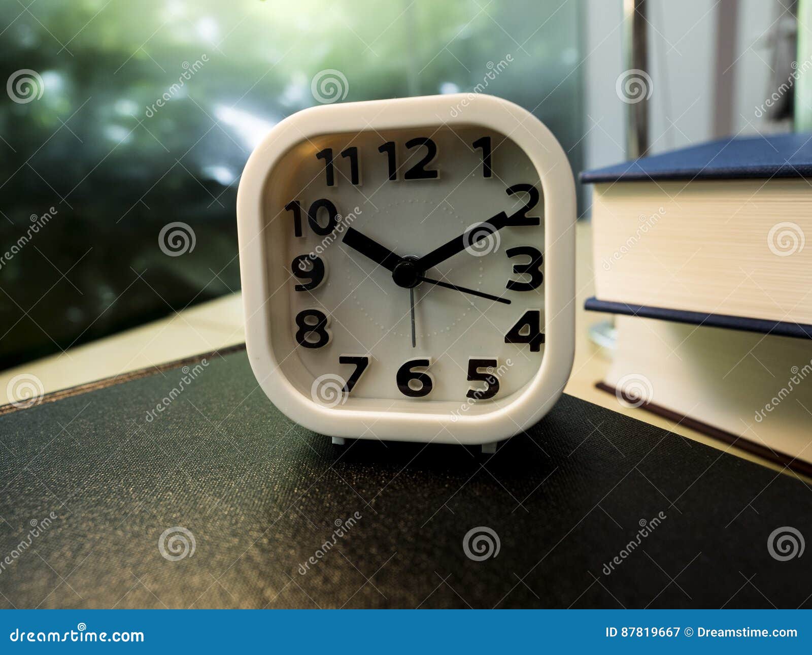 White Alarm Clock beside the Book Stack on Table. Stock Image - Image ...