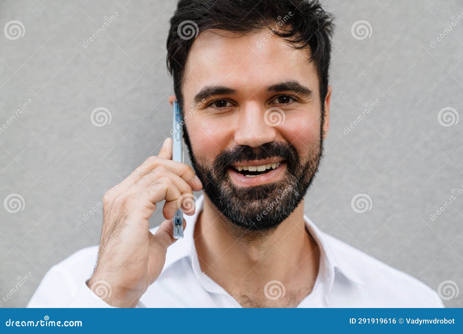 White Bearded Man Talking On Mobile Phone While Standing By Wall Stock