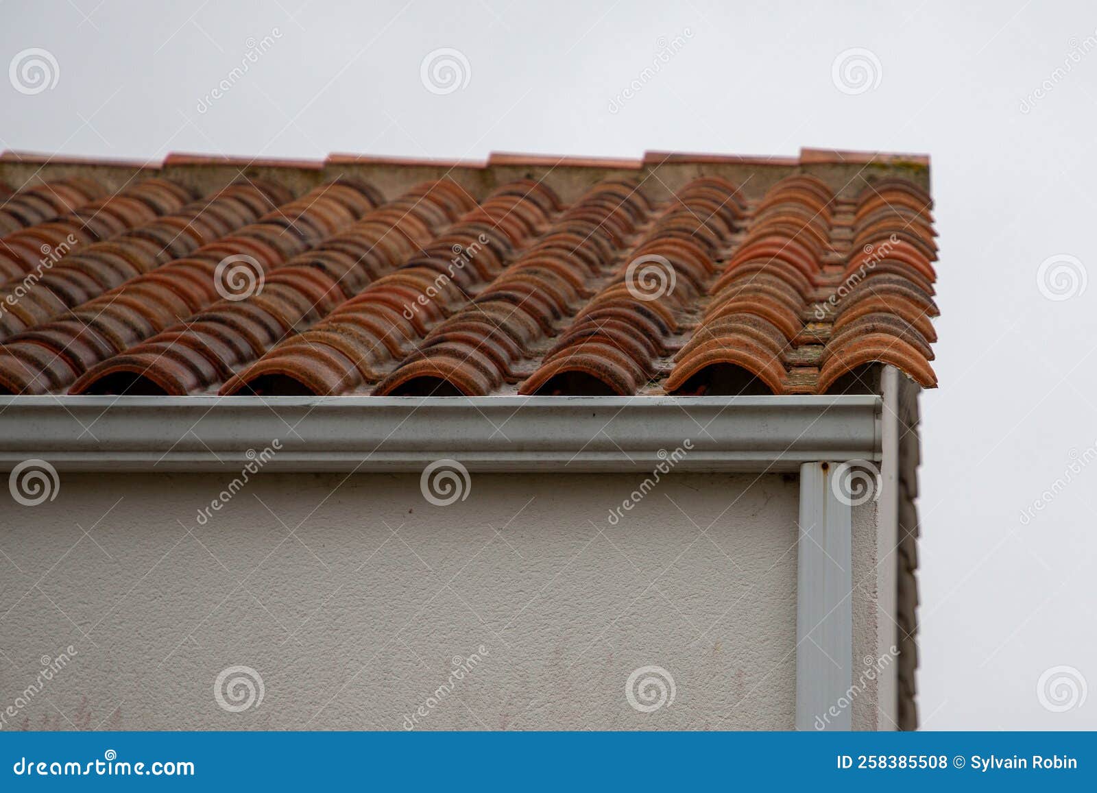 White Beige Gutter on the Roof of the Building and Downpipe on the Wall ...