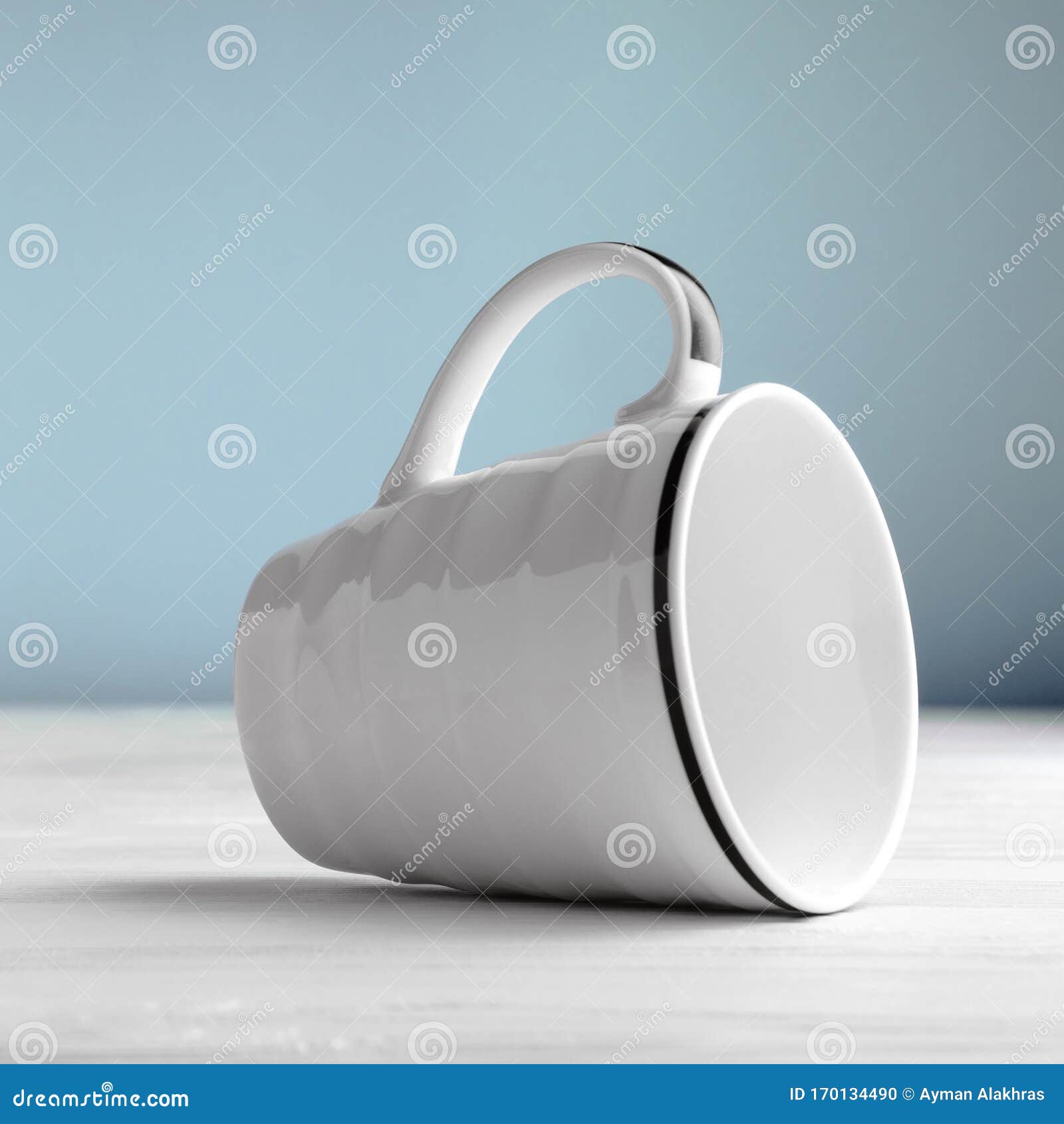 White Blank Mug Lying on Side on White Wooden Table and Blue Background ...
