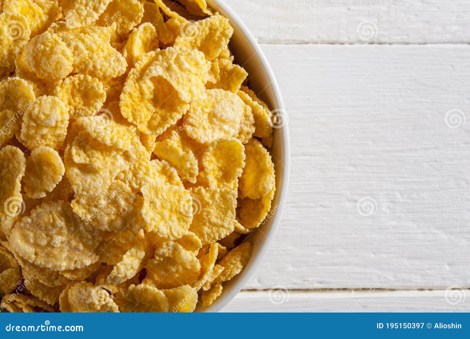 White Bowl with Cornflakes on a White Wooden Table. Occupies the Left ...