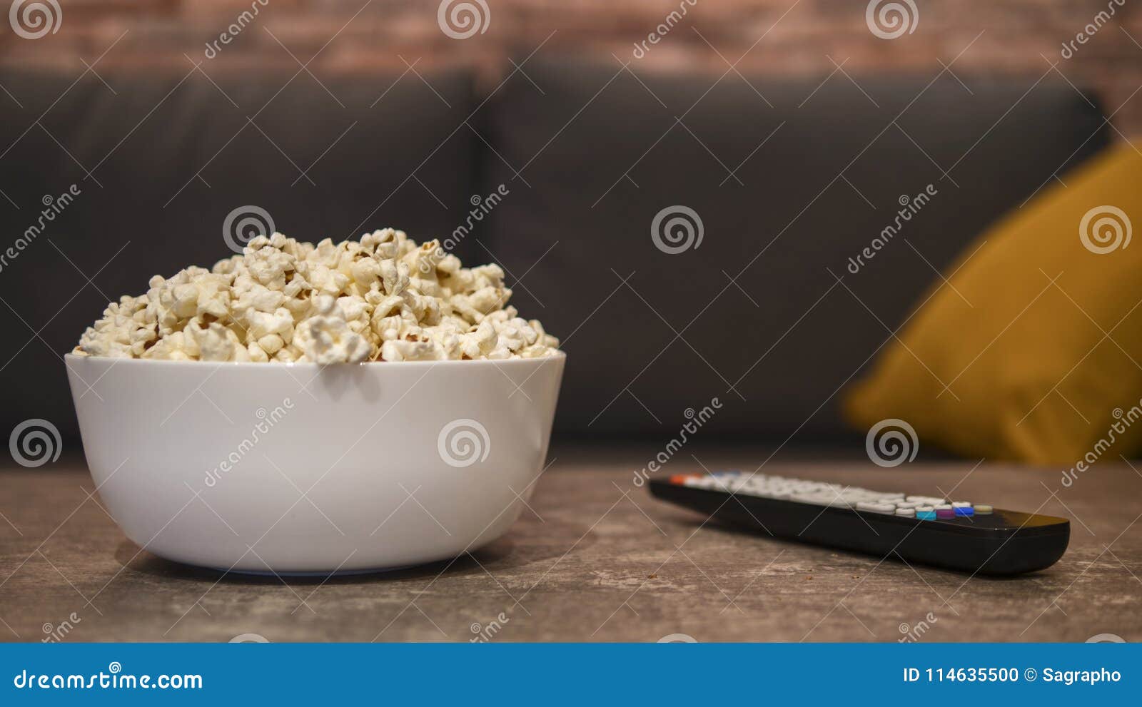 White Bowl of Popcorn and Remote Control in Front of a Couch Stock ...