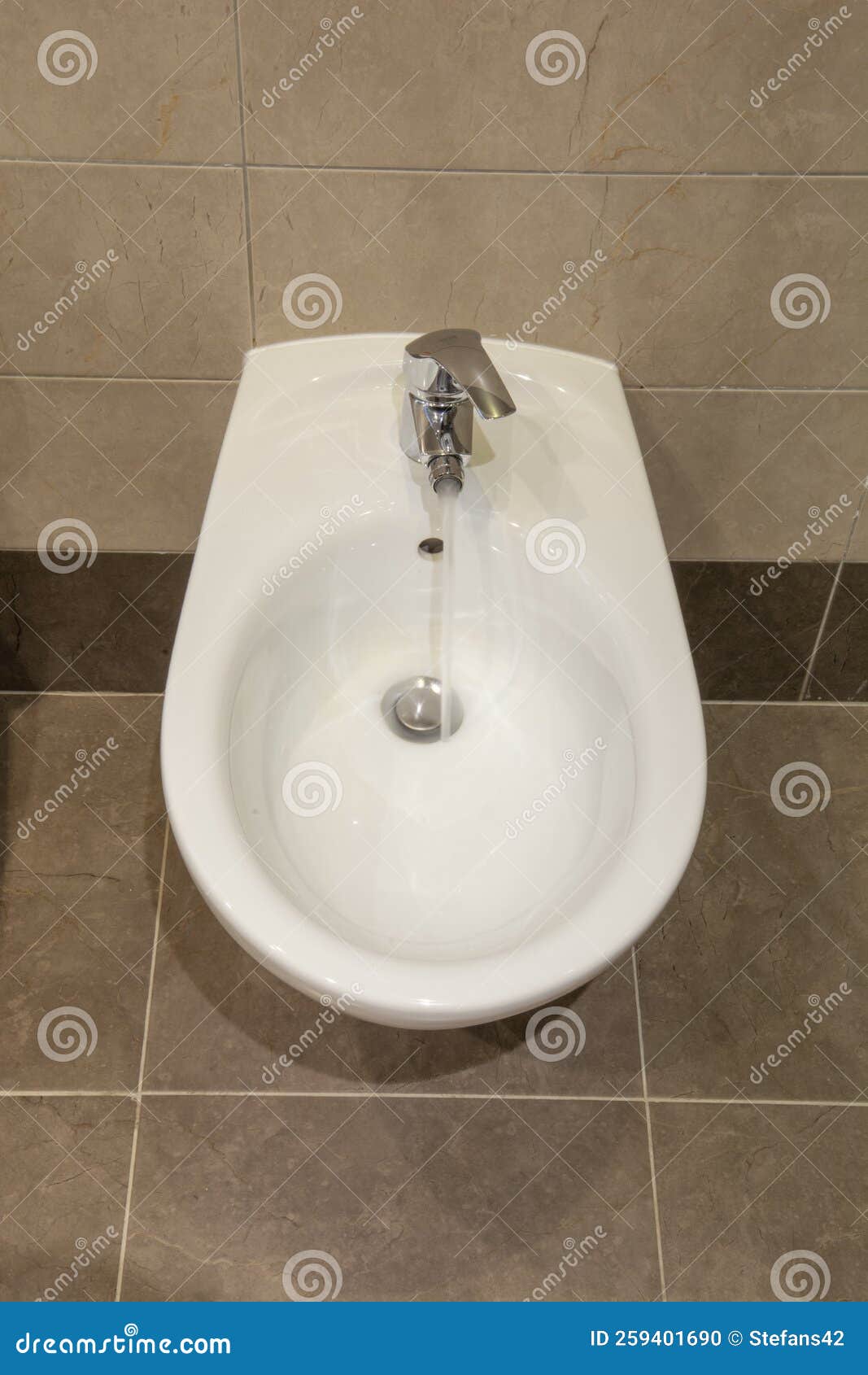 White Ceramic Bidet with a Running Water in Modern Bathroom. Close Up ...