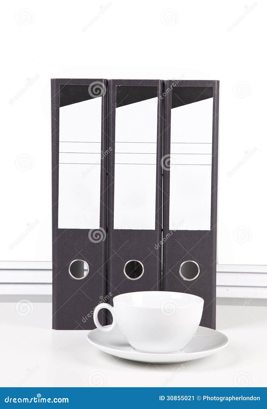 White Coffee Cup and Saucer in Front of Folders at Desk Against White ...