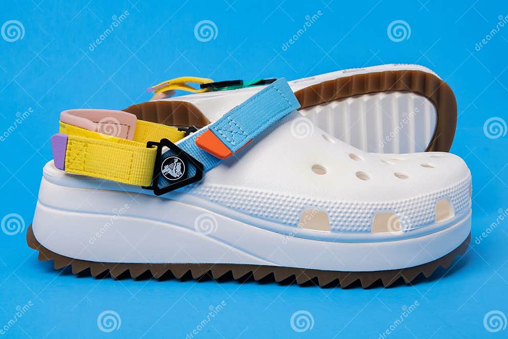 White Crocs Sandals with Colored Straps on a Blue Background Editorial ...