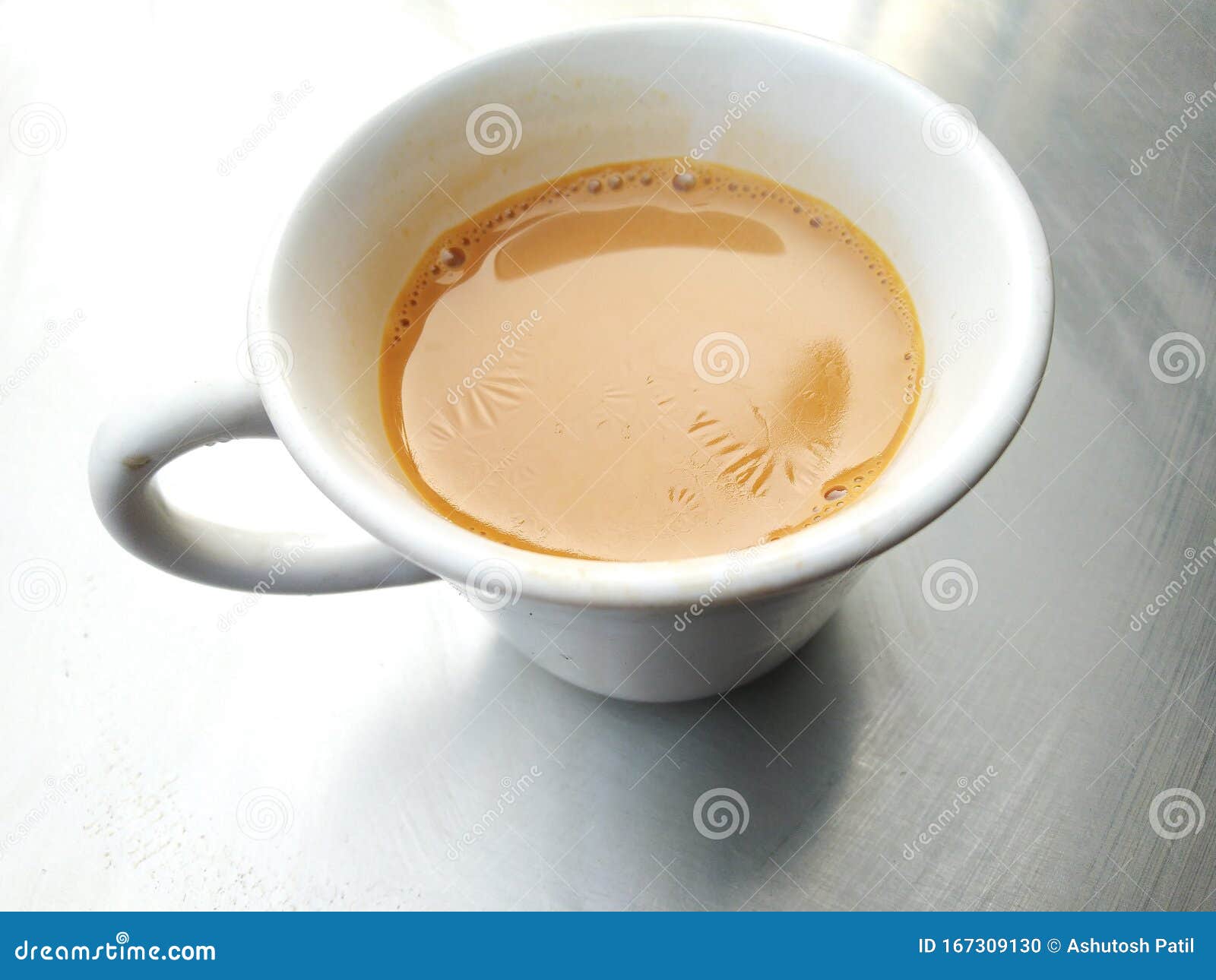 A White Cup of Tea Placed on a Silver Colored Table Having Brown Color ...