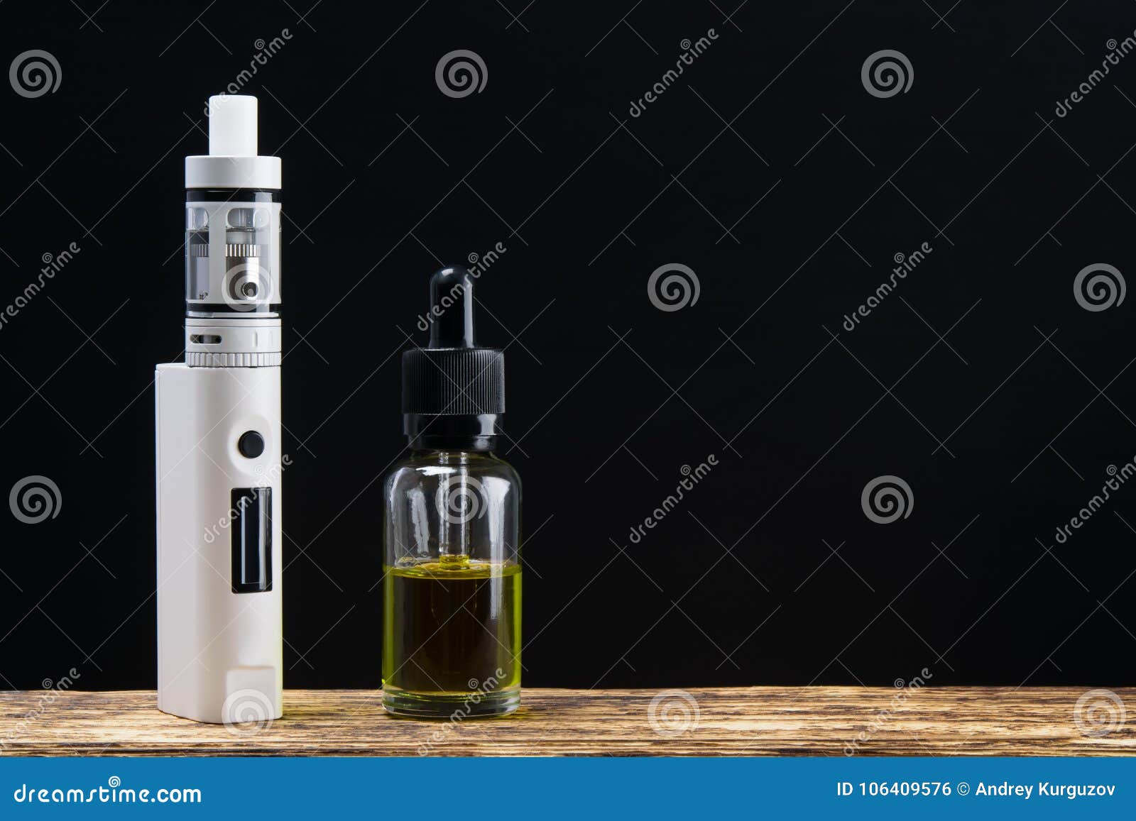 A White Electronic Cigarette is on the Table Next To the Liquid for Its ...