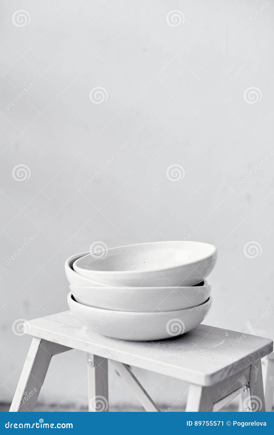 White Empty Ceramic Plates Stand in a Pile Stand on a Wooden Stool ...