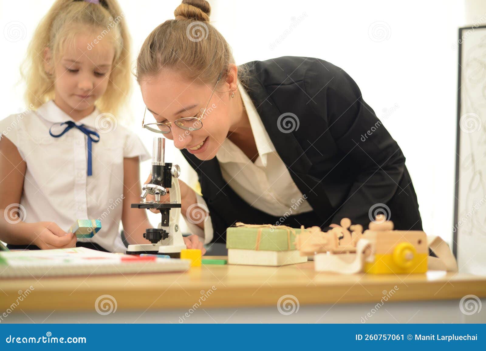 A Little Girl and Her Teacher Study Biology Using a Microscope in the ...