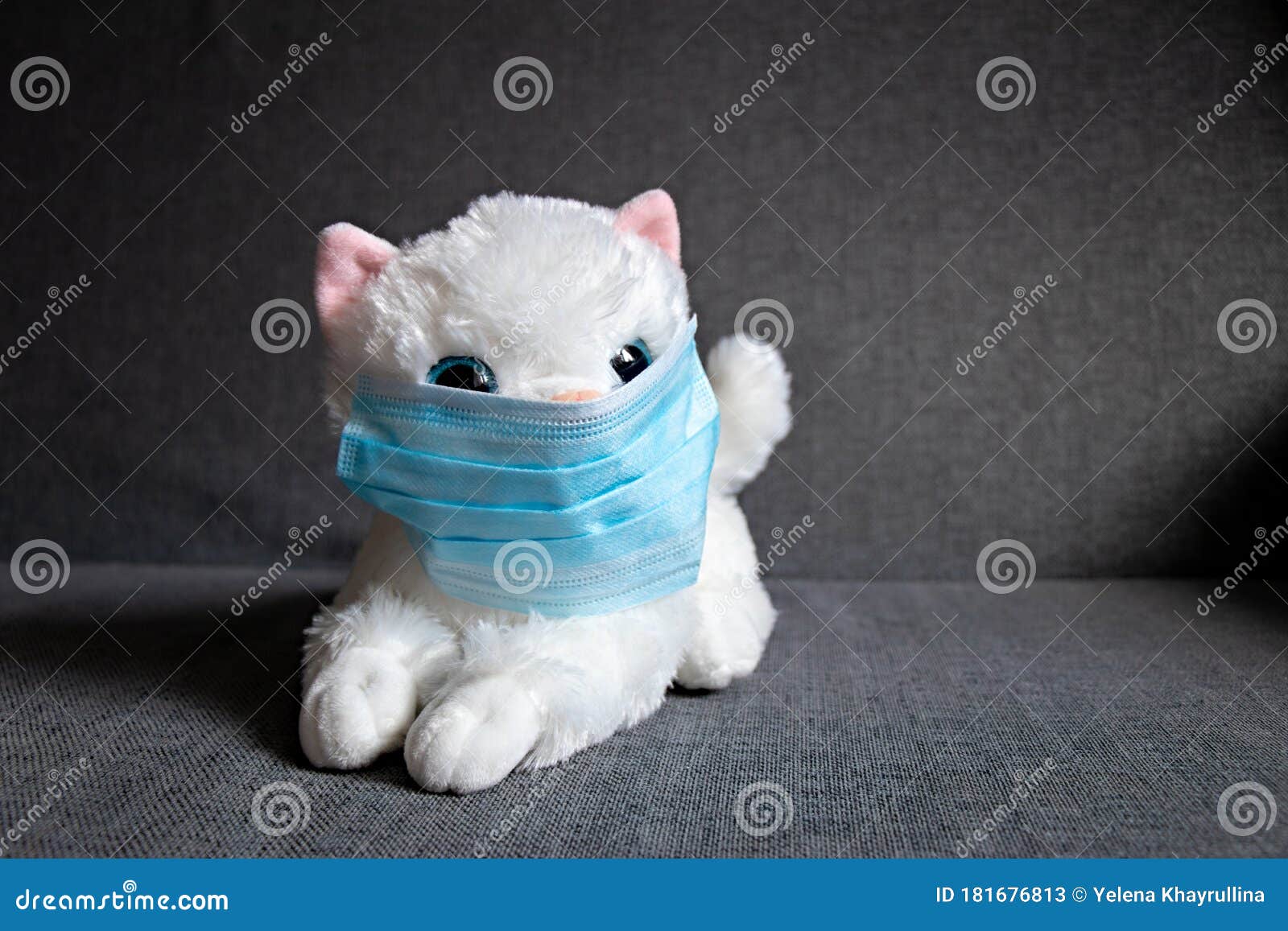 White Fluffy Toy Cat in a Blue Protective Mask on a Gray Background ...