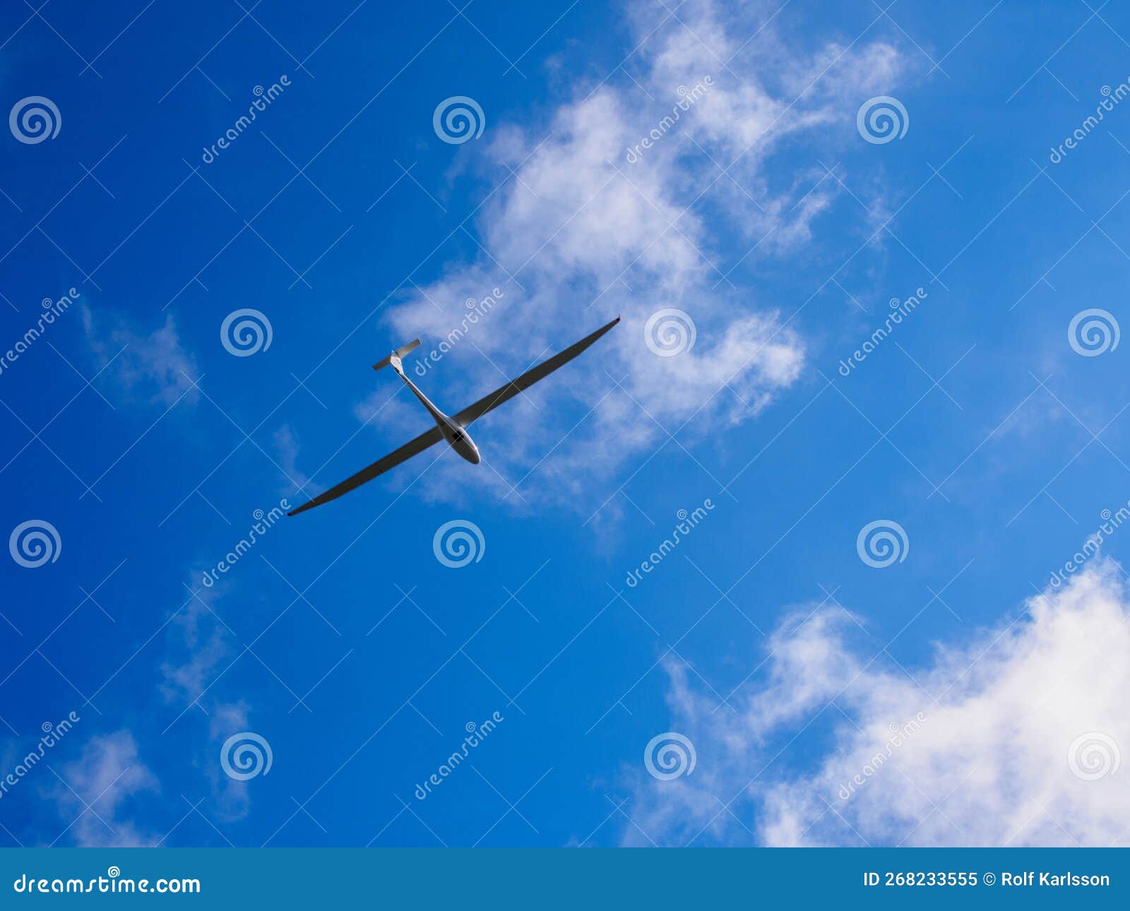 A White Flying Glider Seen from Below with Blue Sky and White Clouds ...