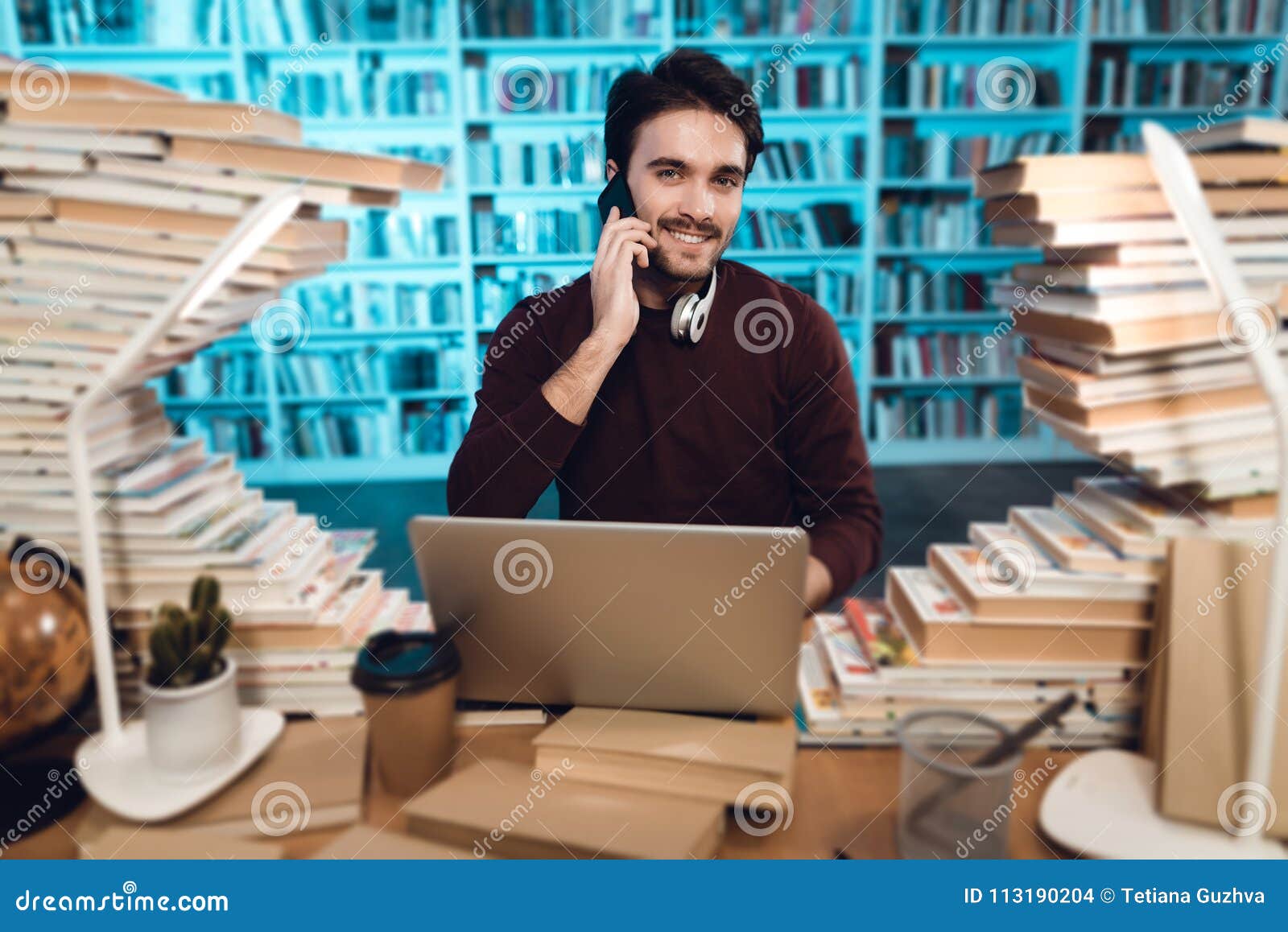 White Guy Surrounded by Books in Library. Student is Using Laptop and ...