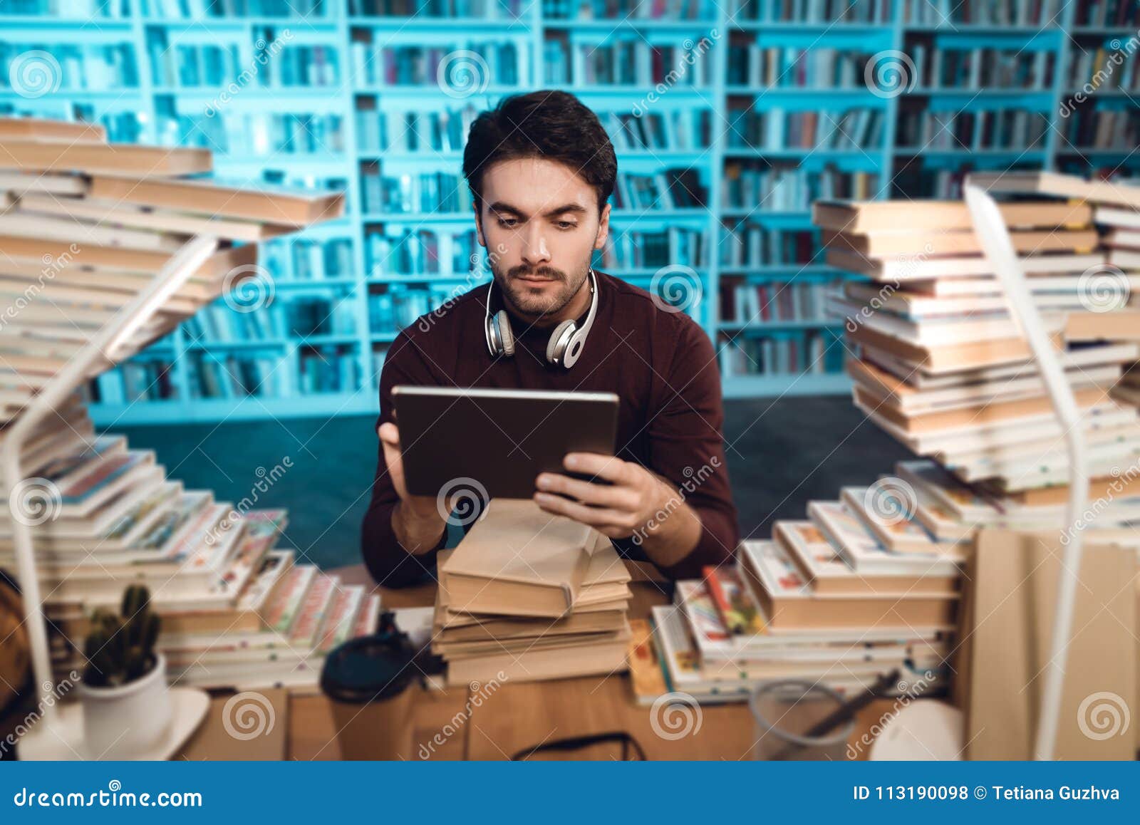 White Guy Surrounded by Books in Library. Student is Using Tablet ...