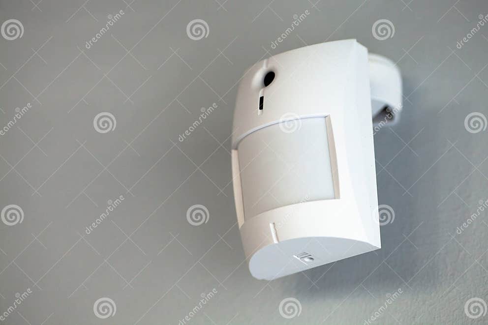 A White Motion Sensor Camera on a Gray Wall, Providing Security and ...