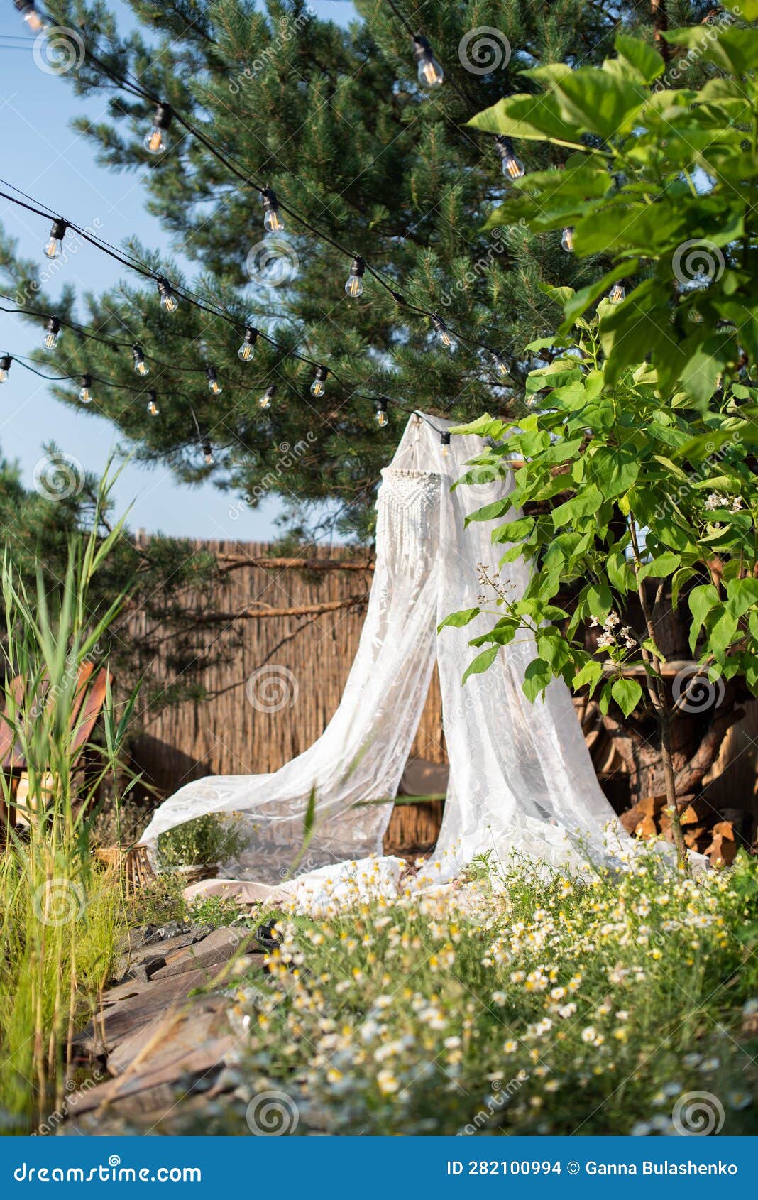 A White Net Canopy with a Chandelier and Cushions Hangs from a Pine ...