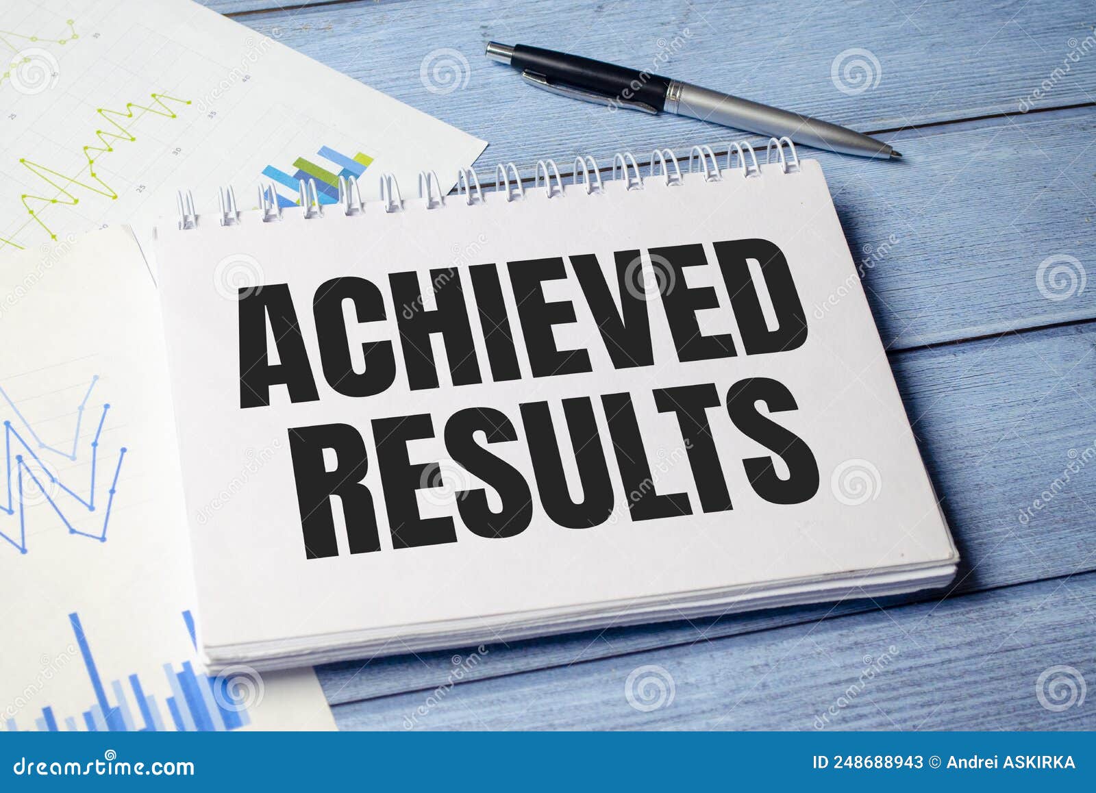 White Notebook with the Text ACHIEVED RESULTS with Charts on Wooden ...