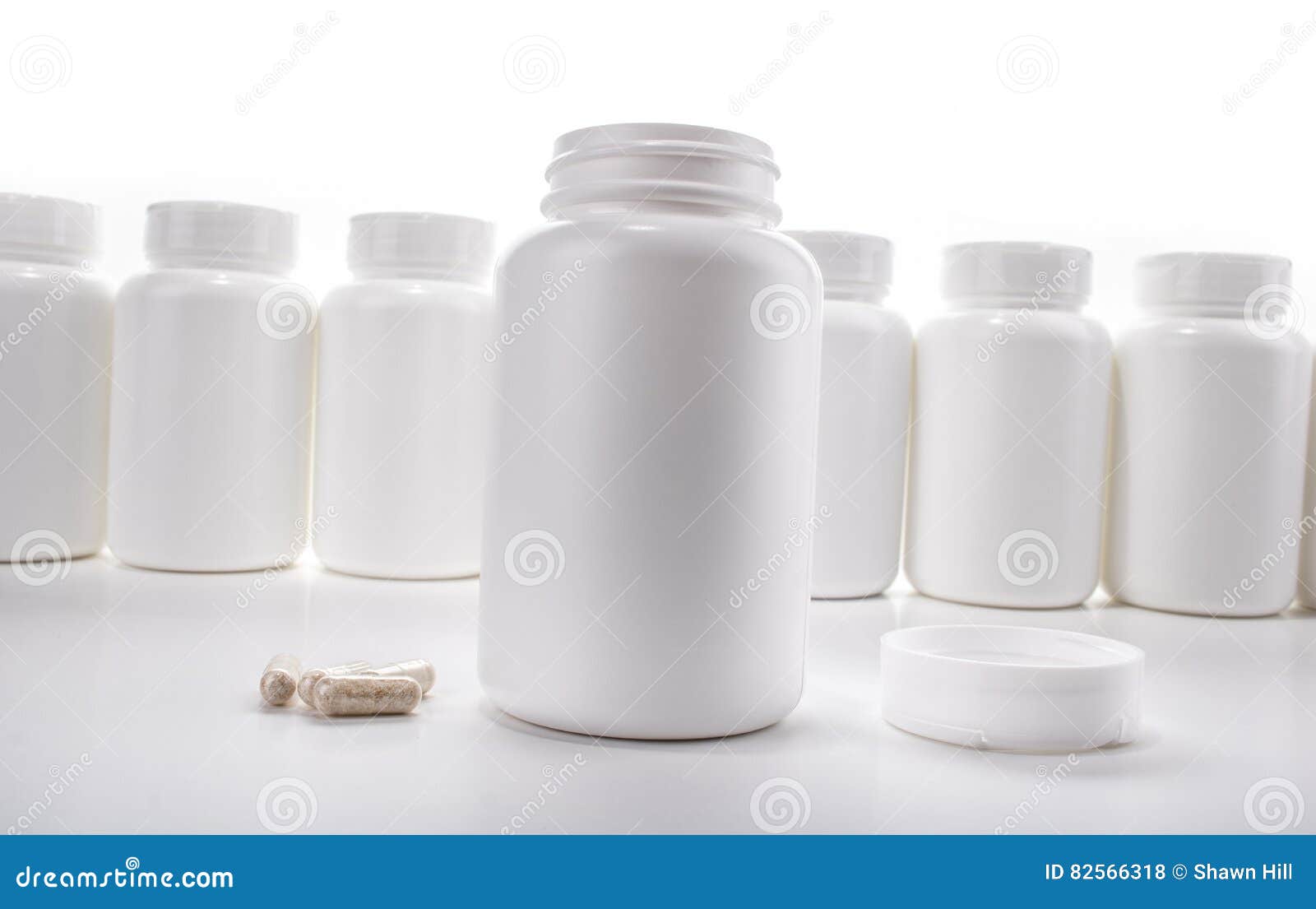 White Pill Bottle Open on Counter between Cap and Brown Capsule Pills ...