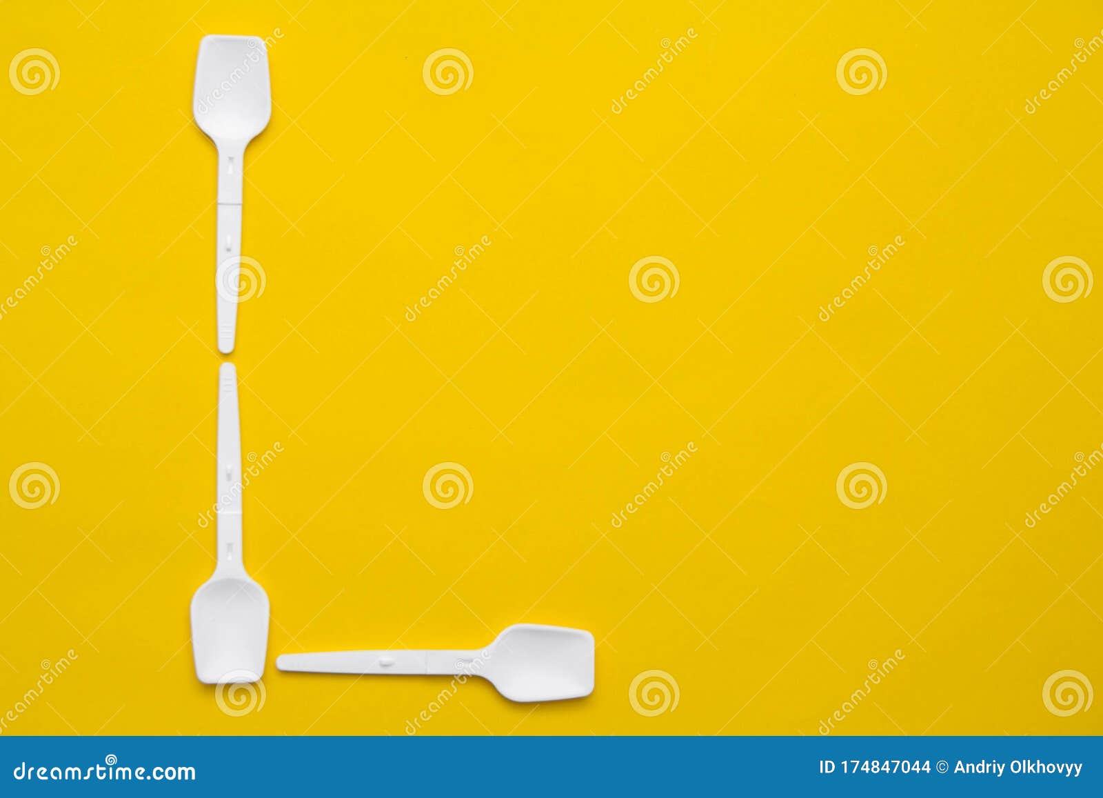 White Plastic Spoons in the Form of Letter L on Yellow Background. Top ...