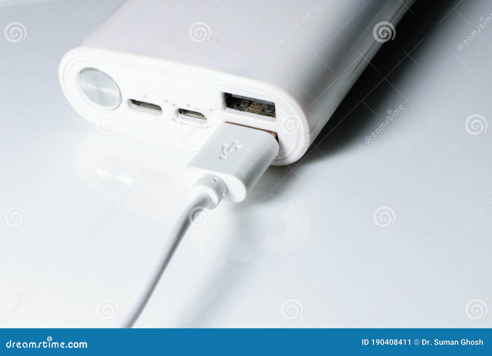 A White Power Bank with USB Ports and Power Button. a Cable is Attached ...