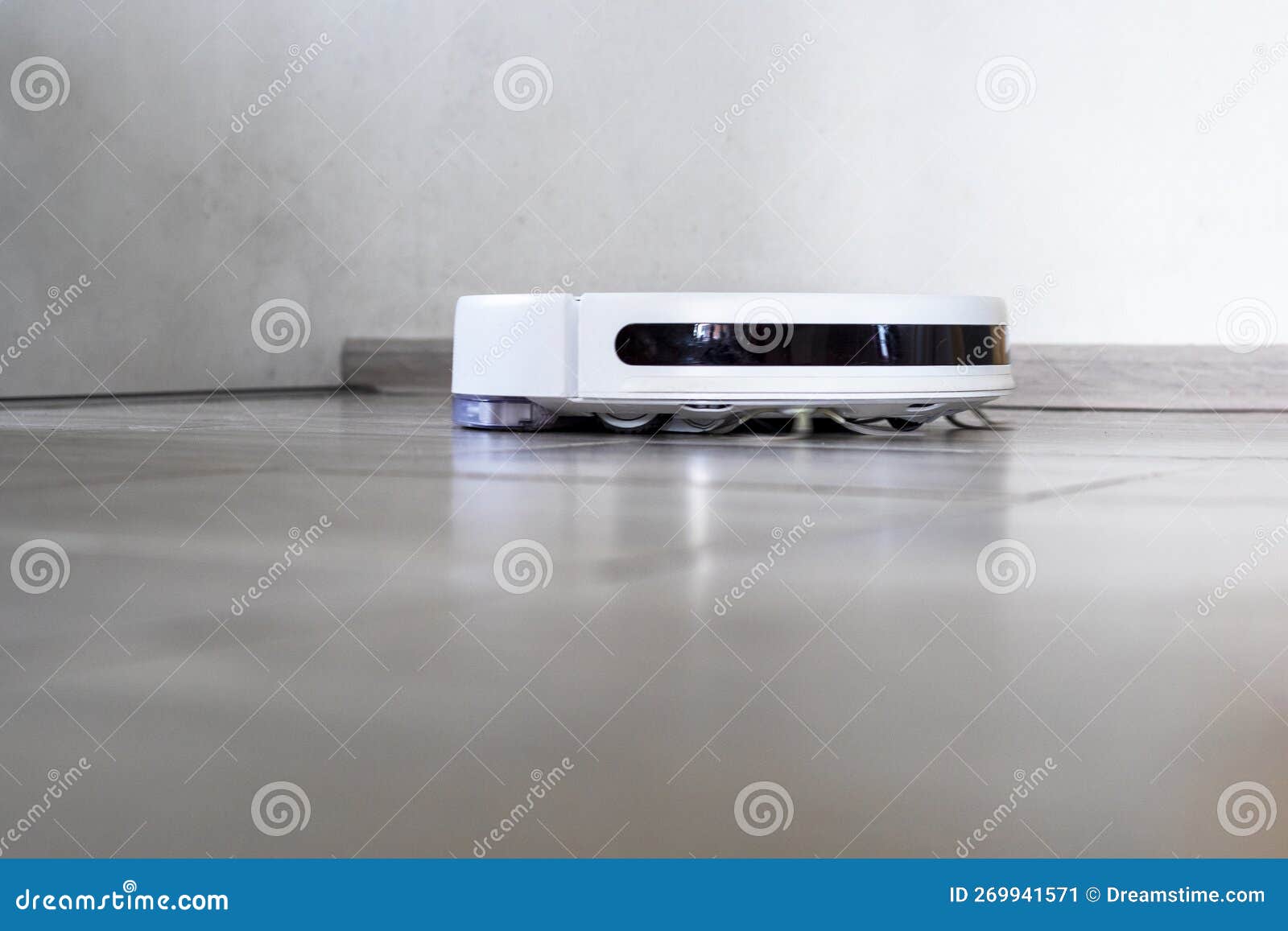 White Robot Vacuum Cleaner Performs Automatic Cleaning in a Bright ...