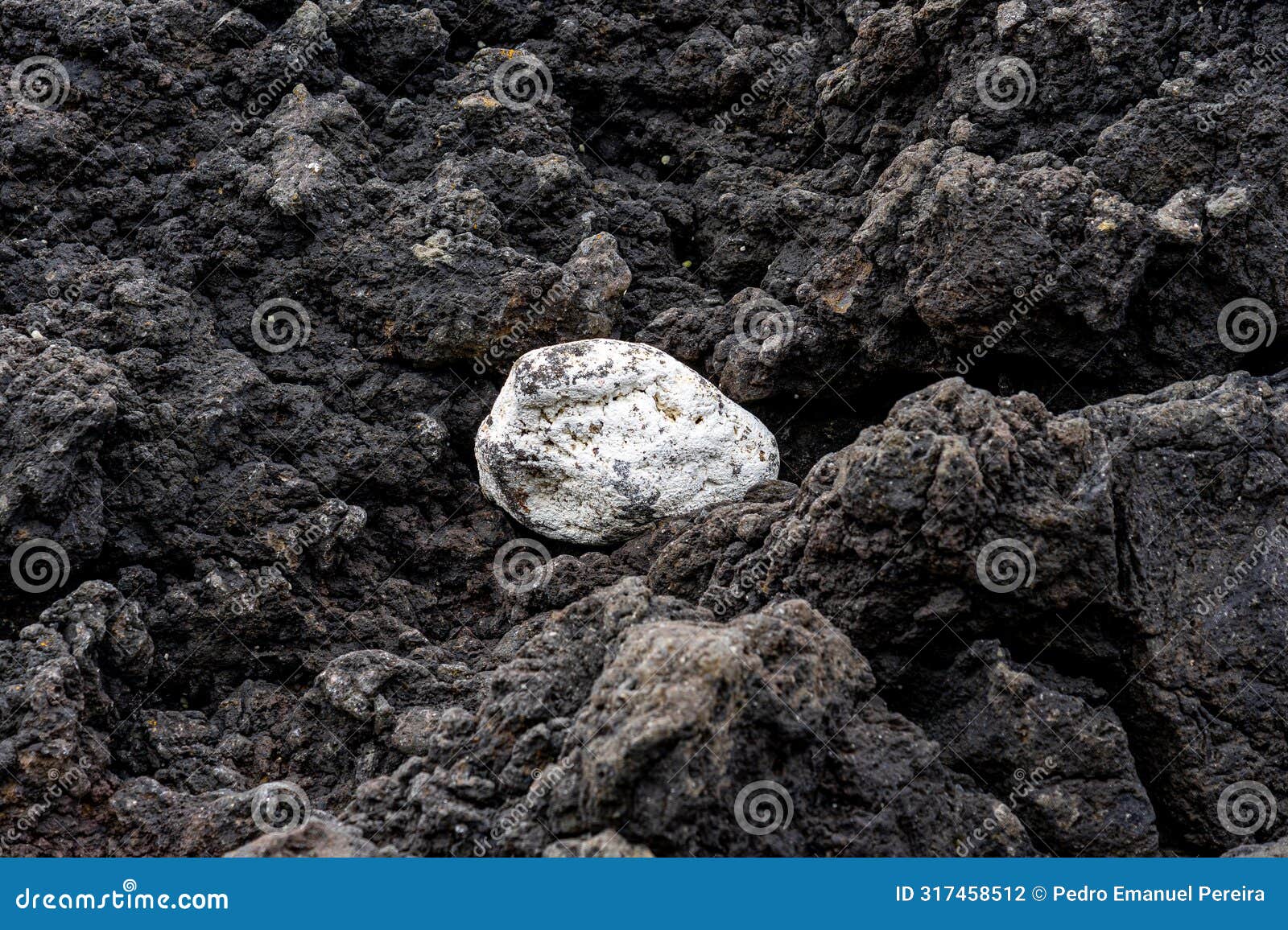 White Round Stone in the Center of Dark Colored Rock Formations with ...