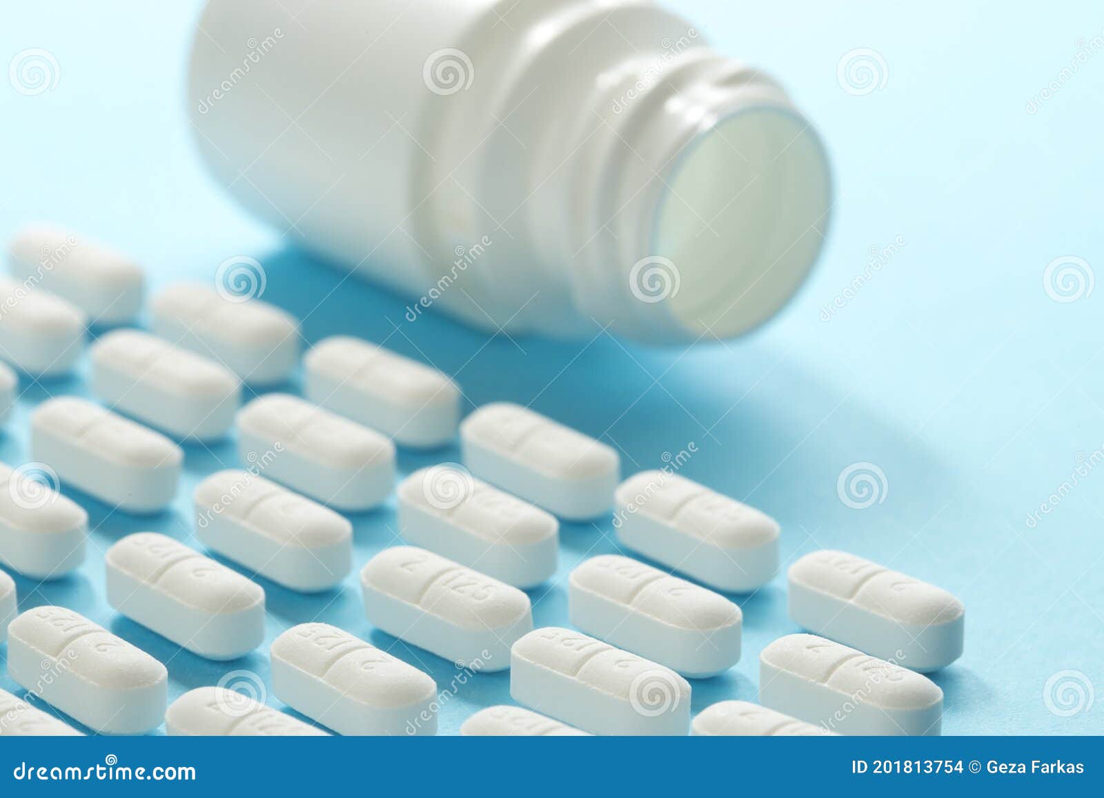 White Rounded Tablets and Plastic Bottle on Blue Background Stock Photo ...