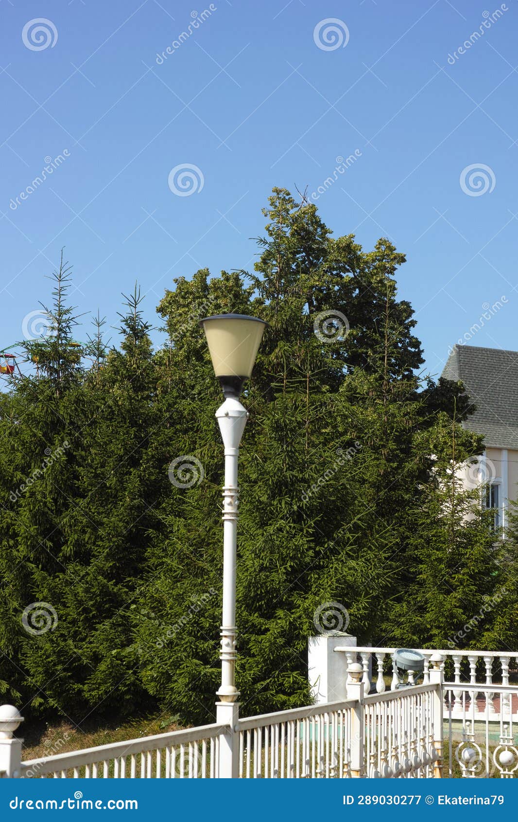 White Street Lamp on a Railing in Front of a Line of Trees Stock Image ...