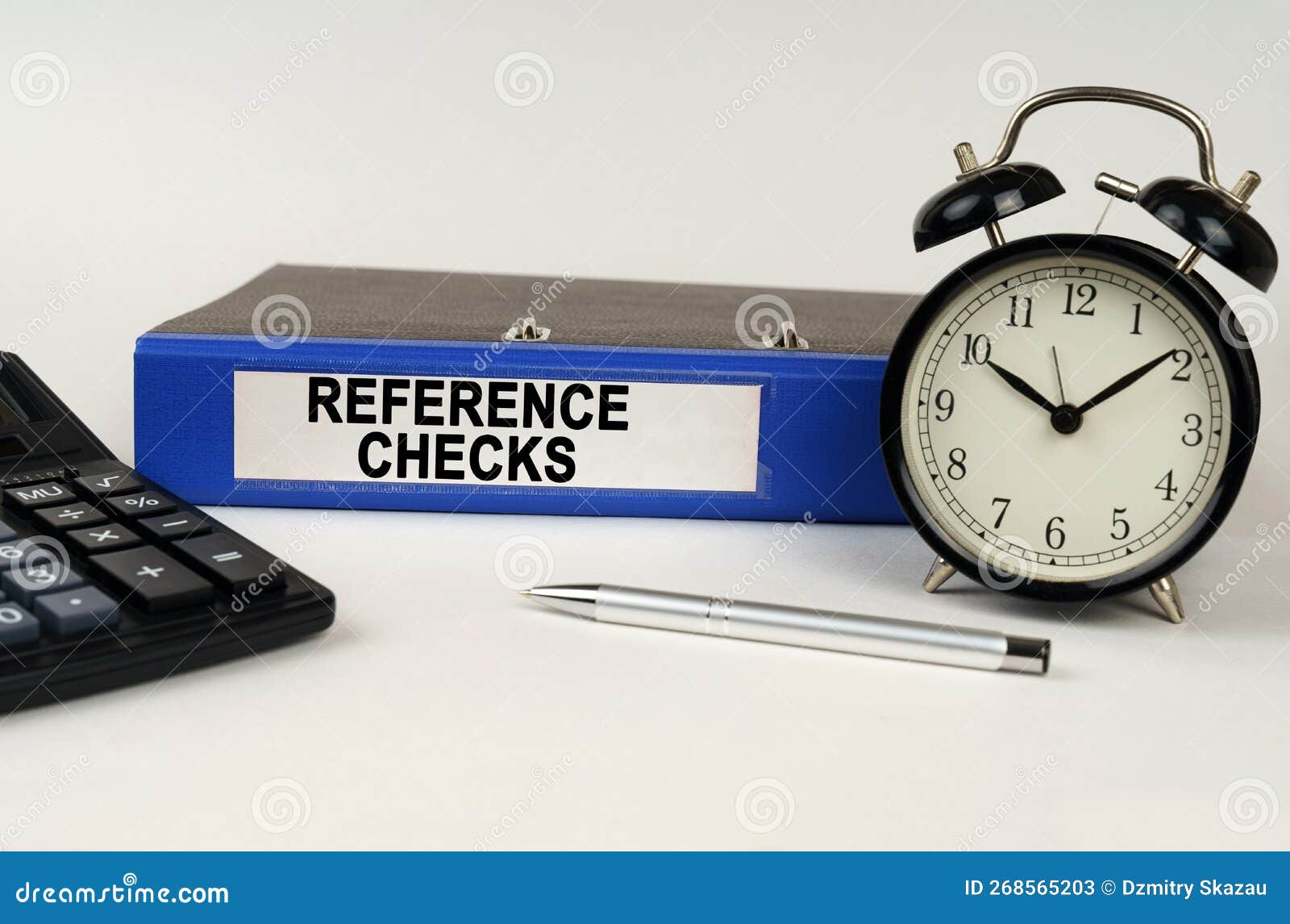 On a White Surface, an Alarm Clock Calculator and a Folder with the ...