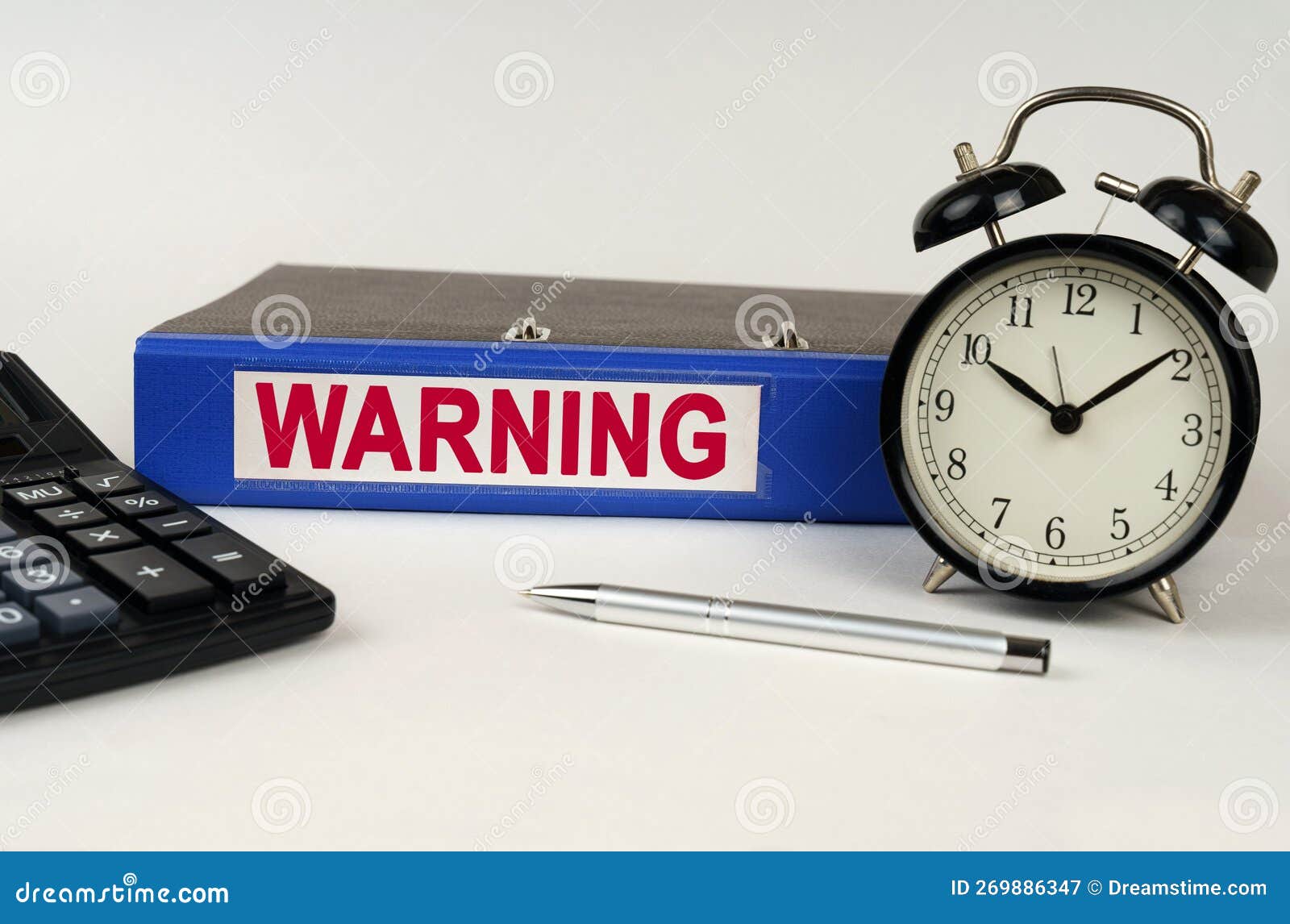 On a White Surface, an Alarm Clock Calculator and a Folder with the ...