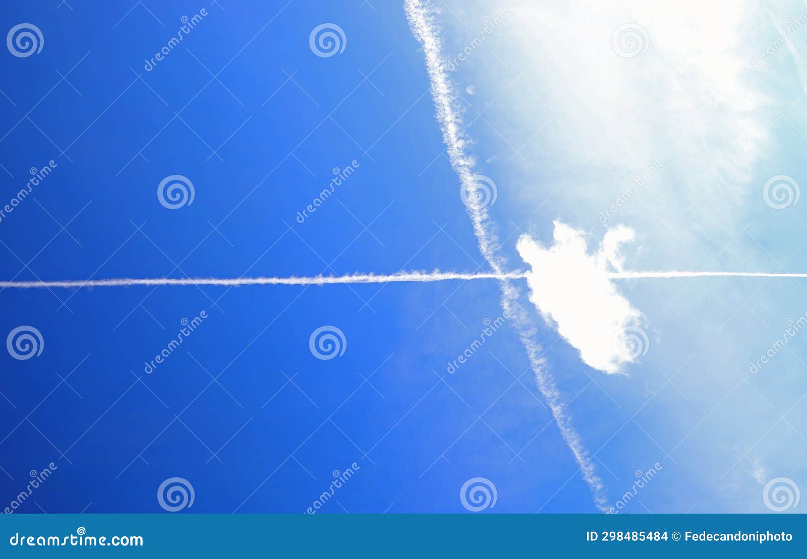 White Trails High in the Blue Sky Crossing a Cloud without Airplanes ...