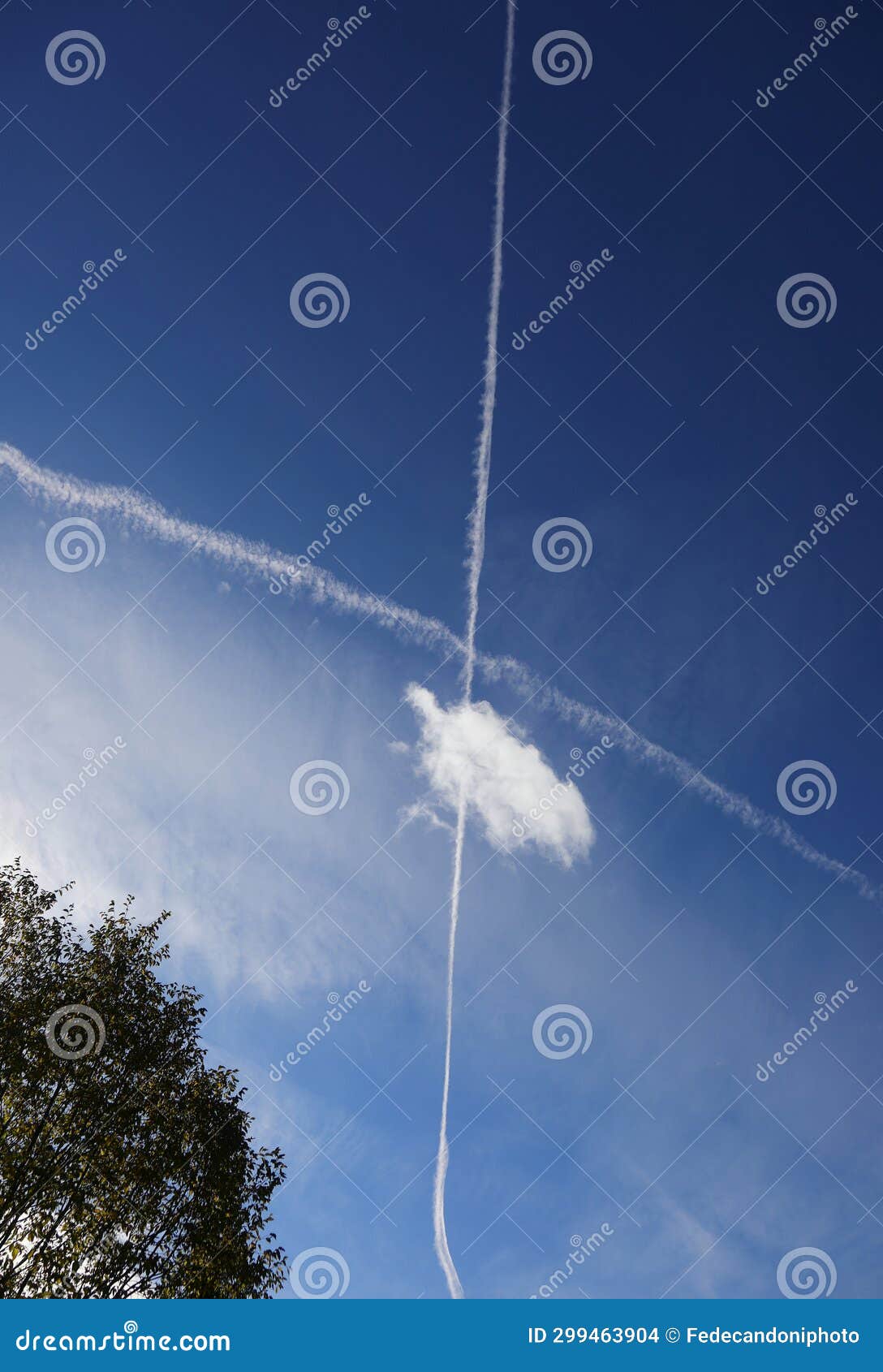 White Trails High in the Blue Sky Crossing a Cloud without Airplanes ...