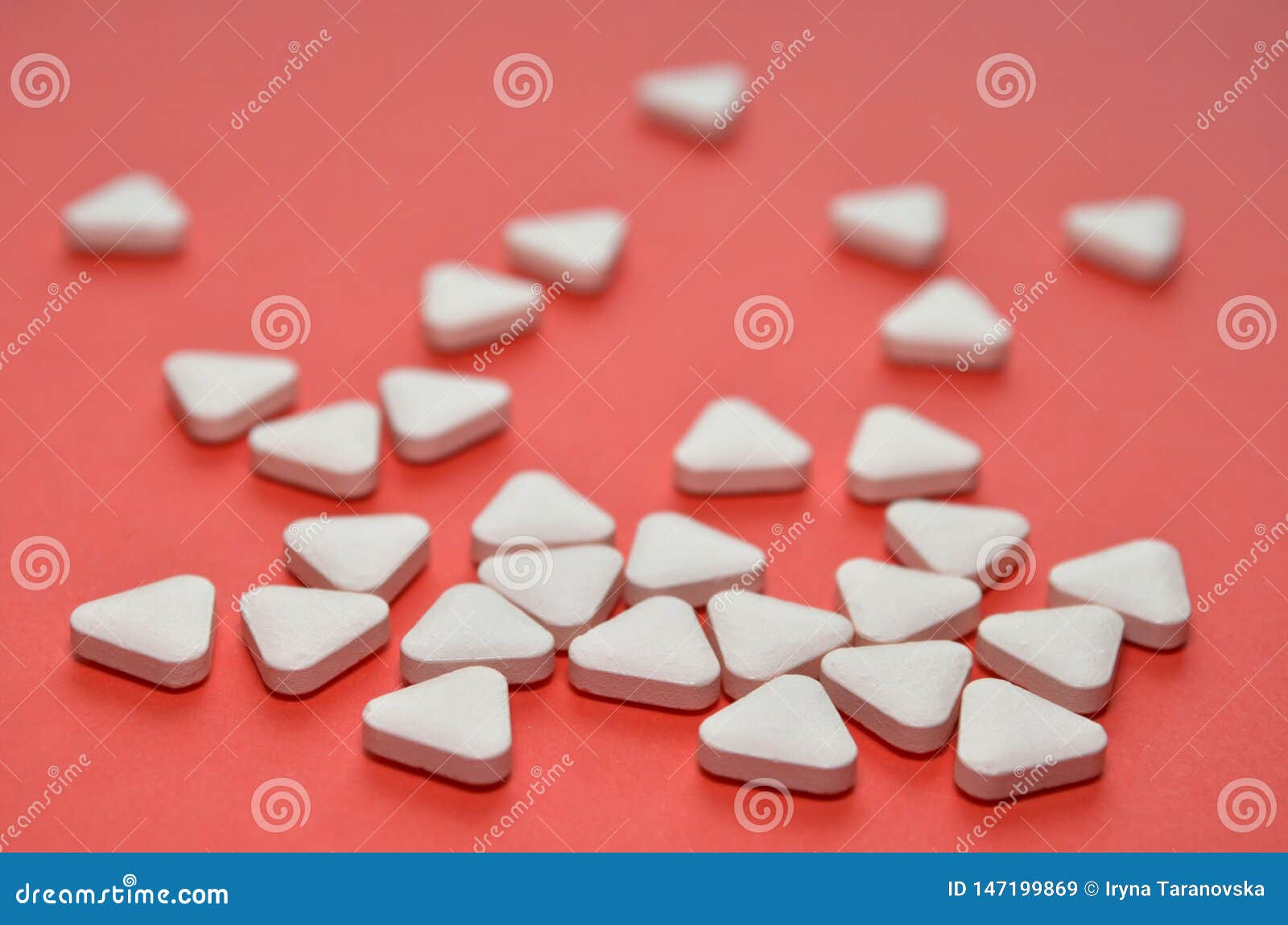 White Triangular Unusual Pills Dispersed on a Pink Background Closeup ...