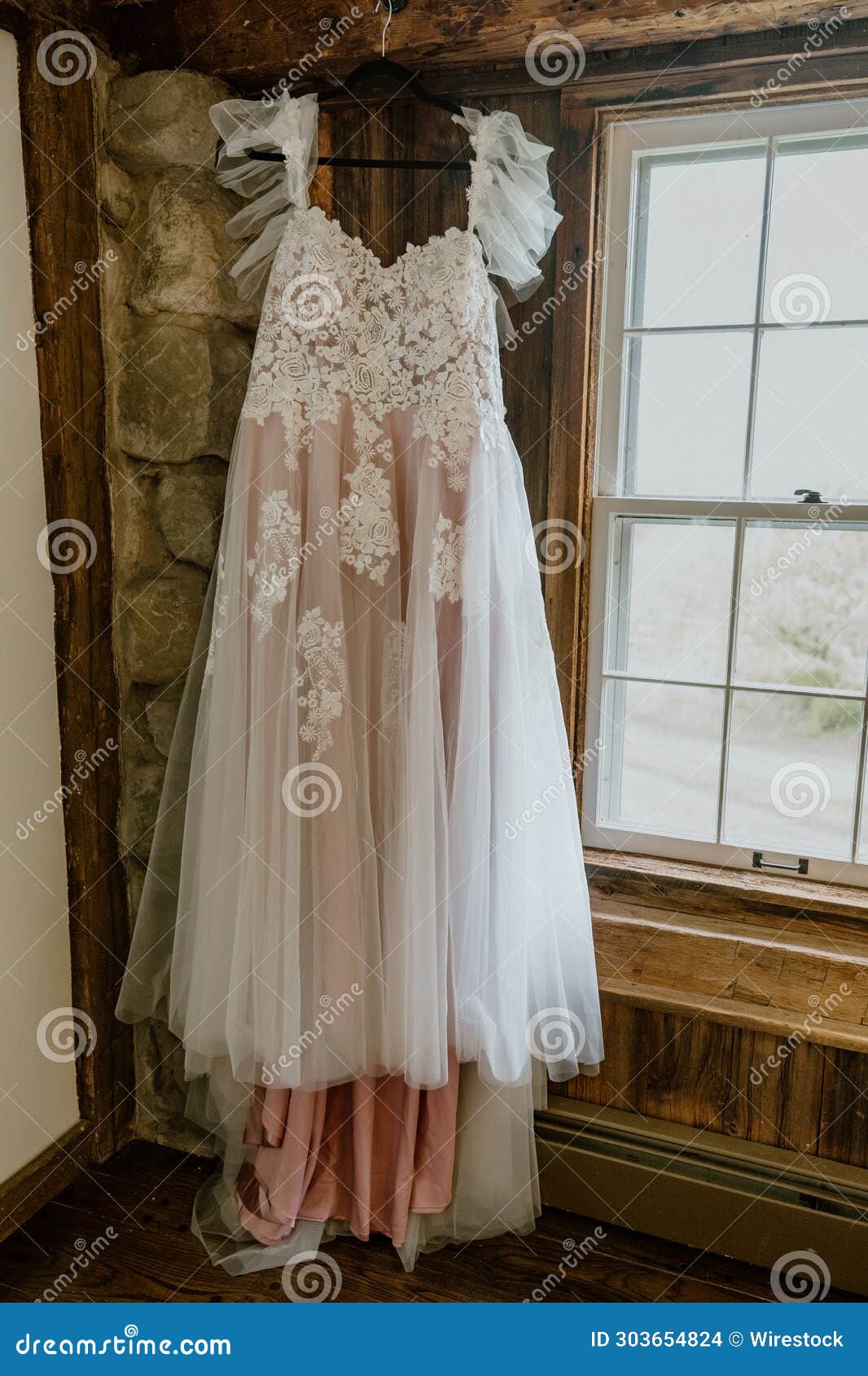 White Wedding Dress Displayed in Front of a Window in an Elegant Cabin ...