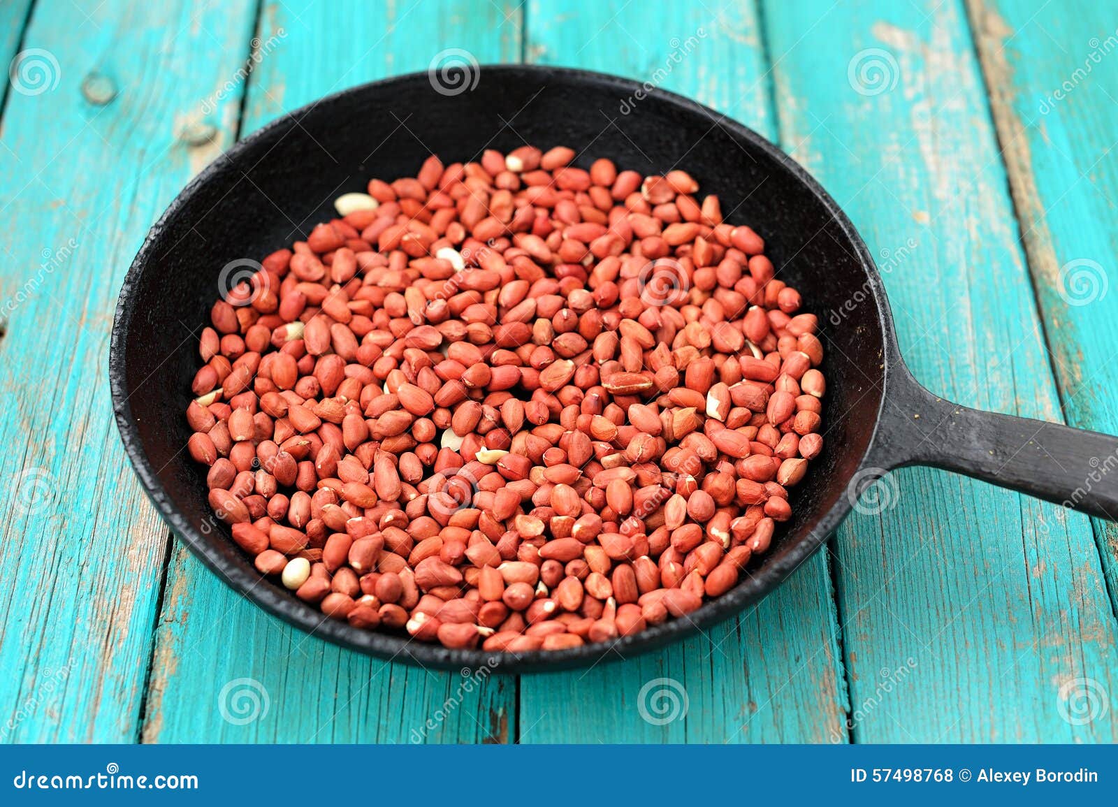 Whole Fried Pink Peanuts in Black Cast Iron Pan on Turquoise Ta Stock ...