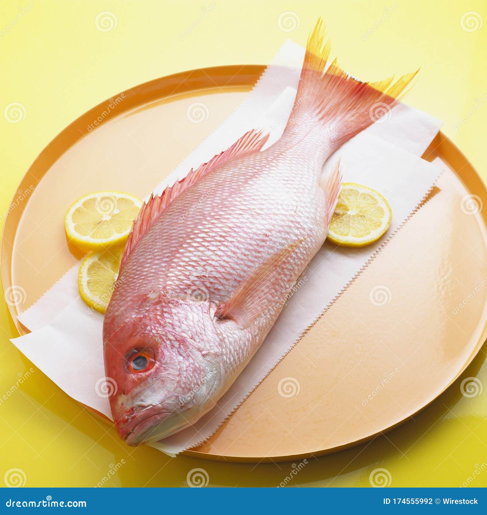 Whole Red Snapper Fish on a Yellow Plate with Lemons on the Side Stock ...