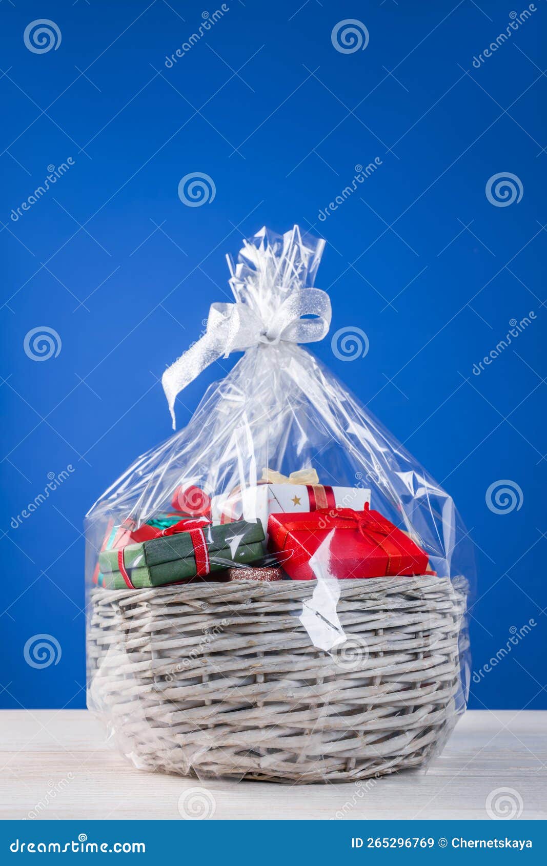 Wicker Basket Full of Gift Boxes on White Wooden Table Against Blue ...