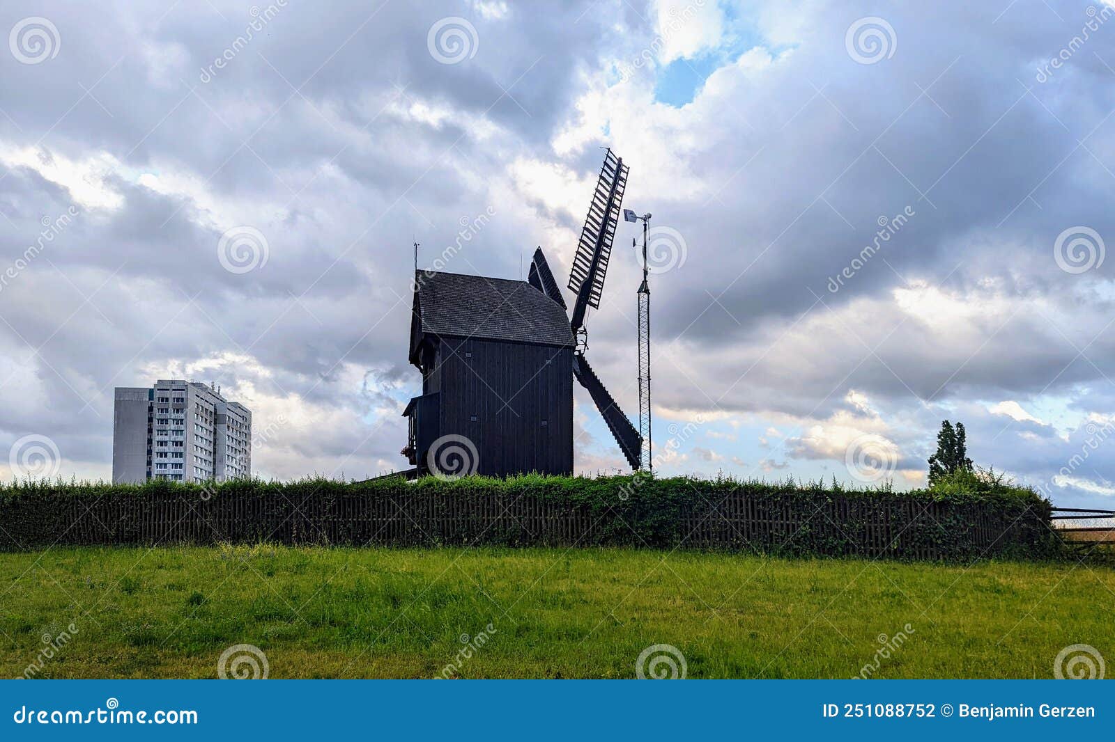 Windmill and High-rise House at the Cloudy Sky and Green Meadow Stock ...
