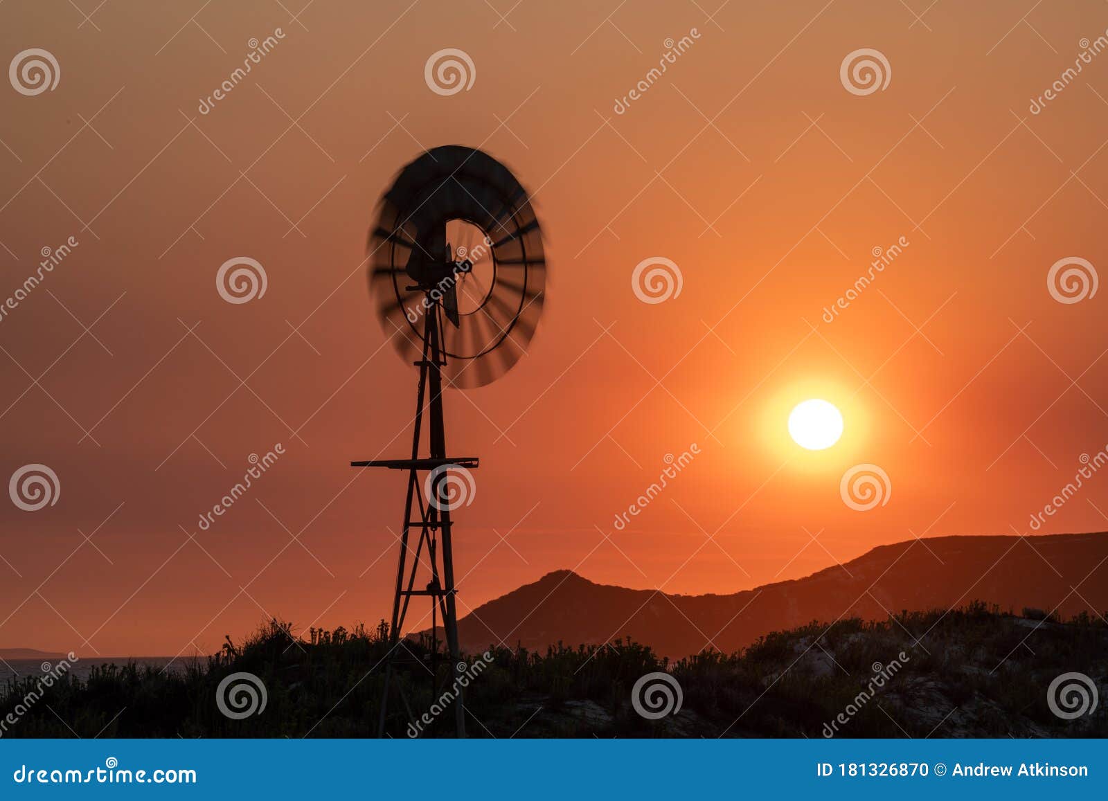 Windmill Spinning in the Wind at Sunset with Orange Red Sky and Yellow ...