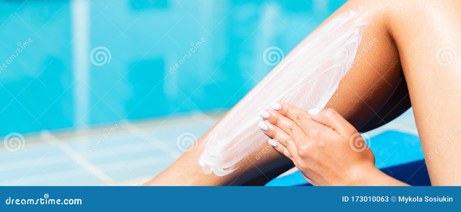 Woman Is Applying Sunscreen On Her Tanned Legs By The Swimming Pool