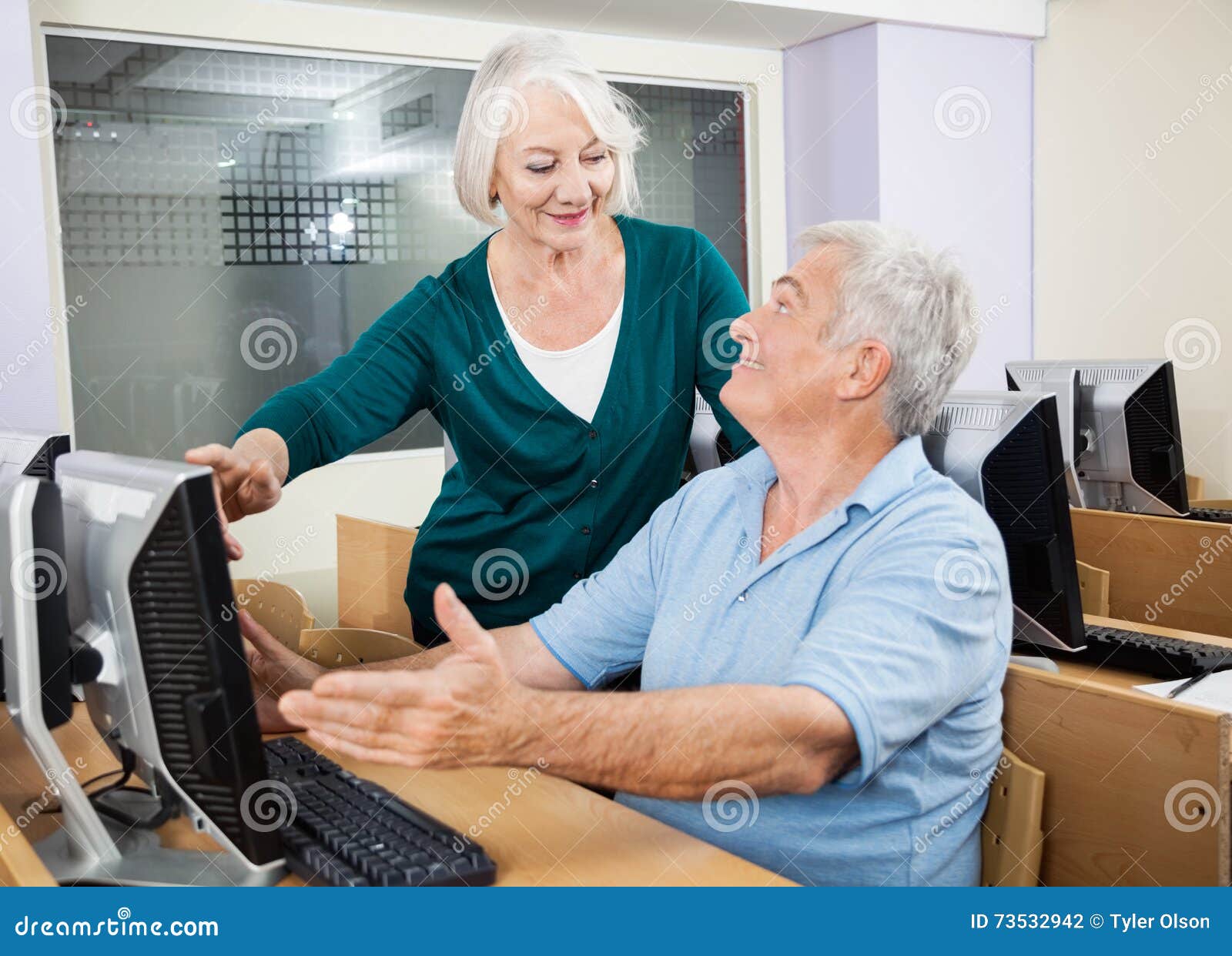 Woman Assisting Classmate in Using Computer at Classroom Stock Photo ...