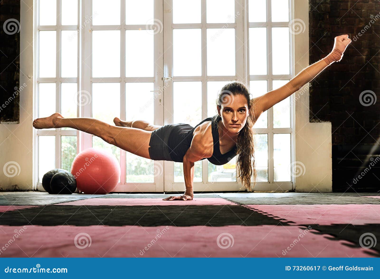 Woman Balancing while Doing a One Hand Push Up Showing Strength Stock ...