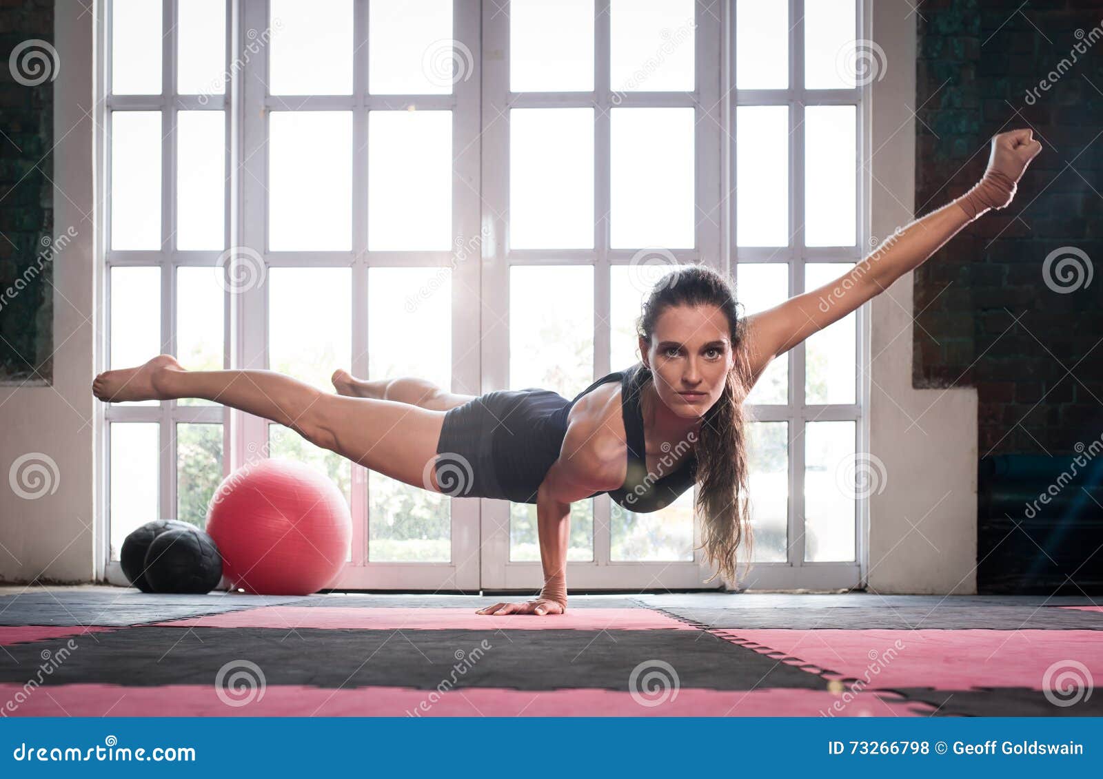 Woman Balancing while Doing a One Hand Push Up Showing Strength Stock ...