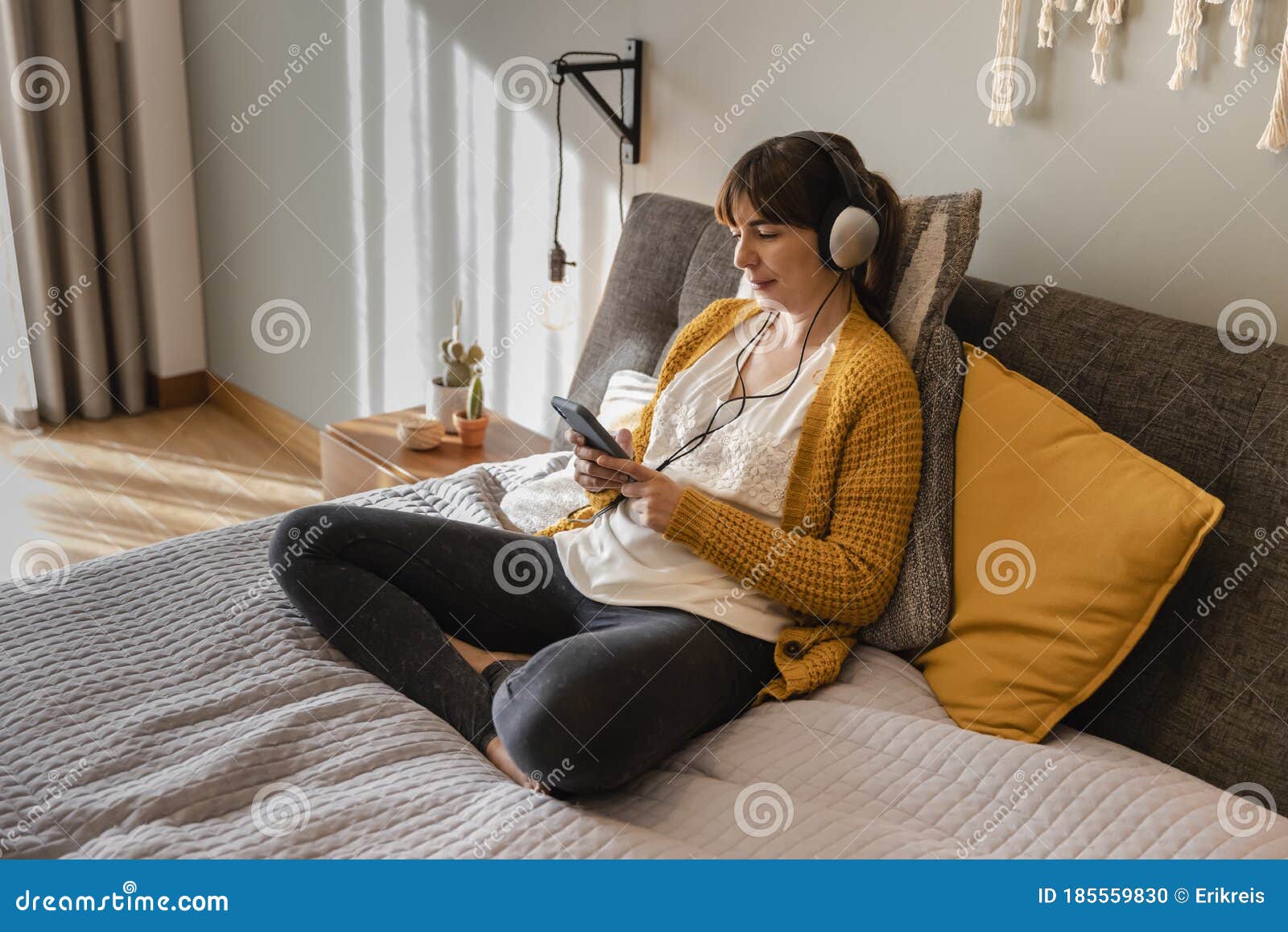 Woman on bed texting stock photo. Image of listening - 185559830